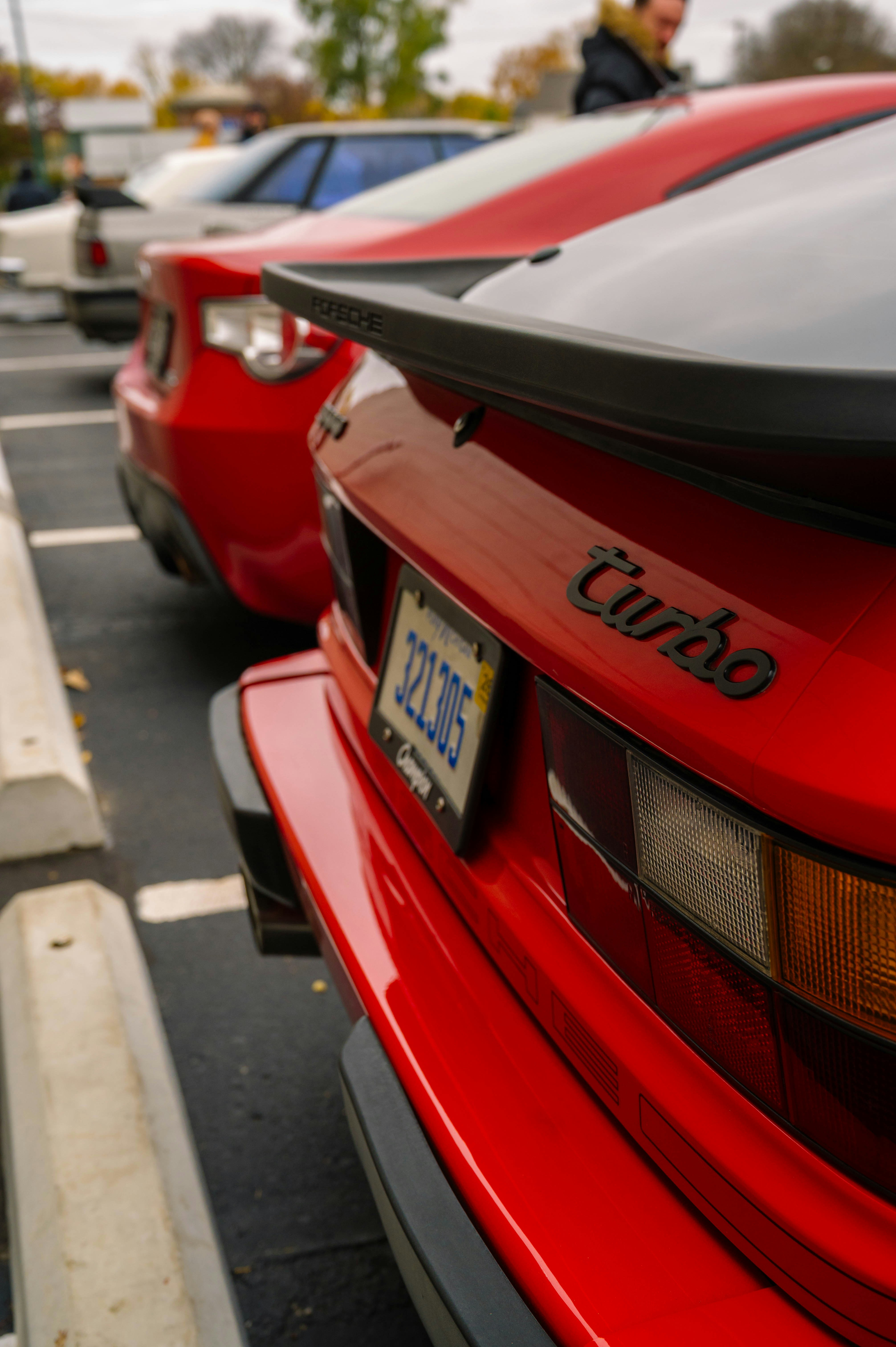 Scarlet Turbo in Parking Lot: A Close-Up of Porsche Rear Wing and Badge