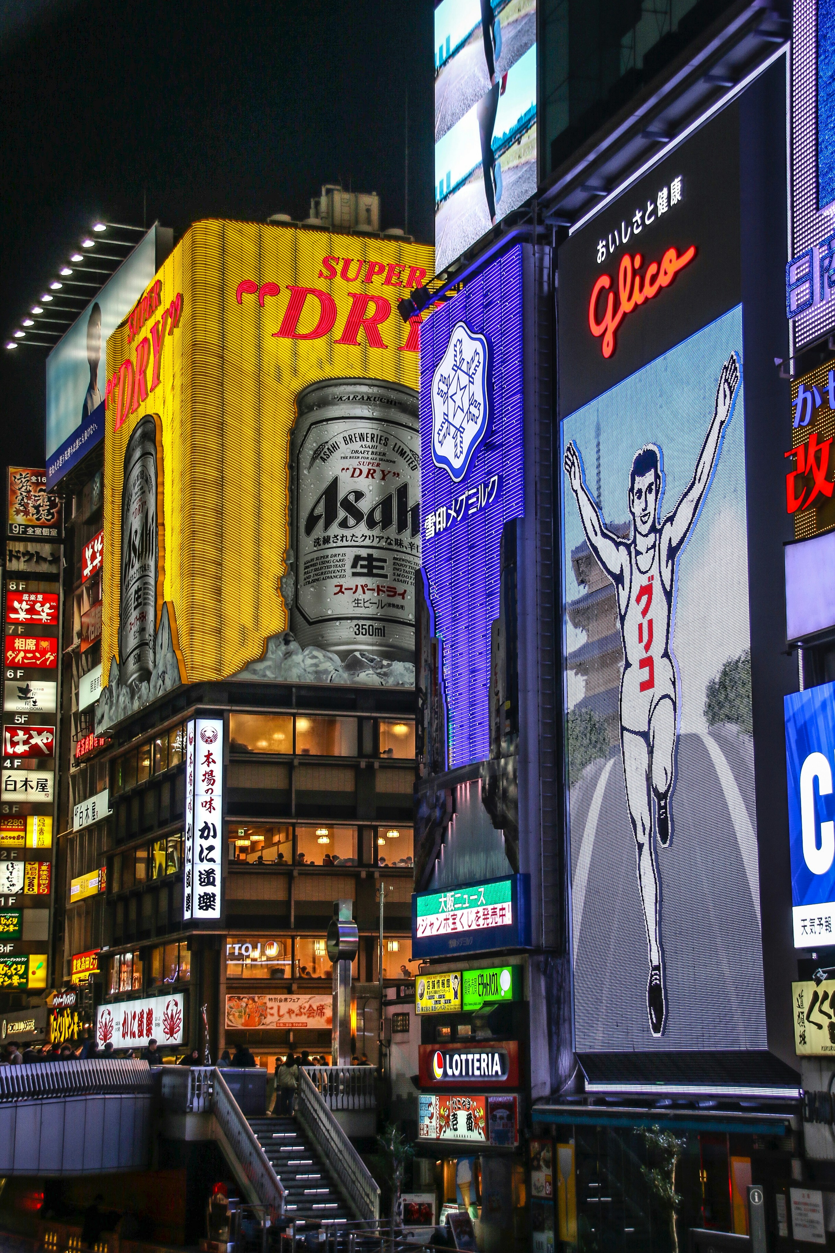 Neon signs illuminate a city street at night.