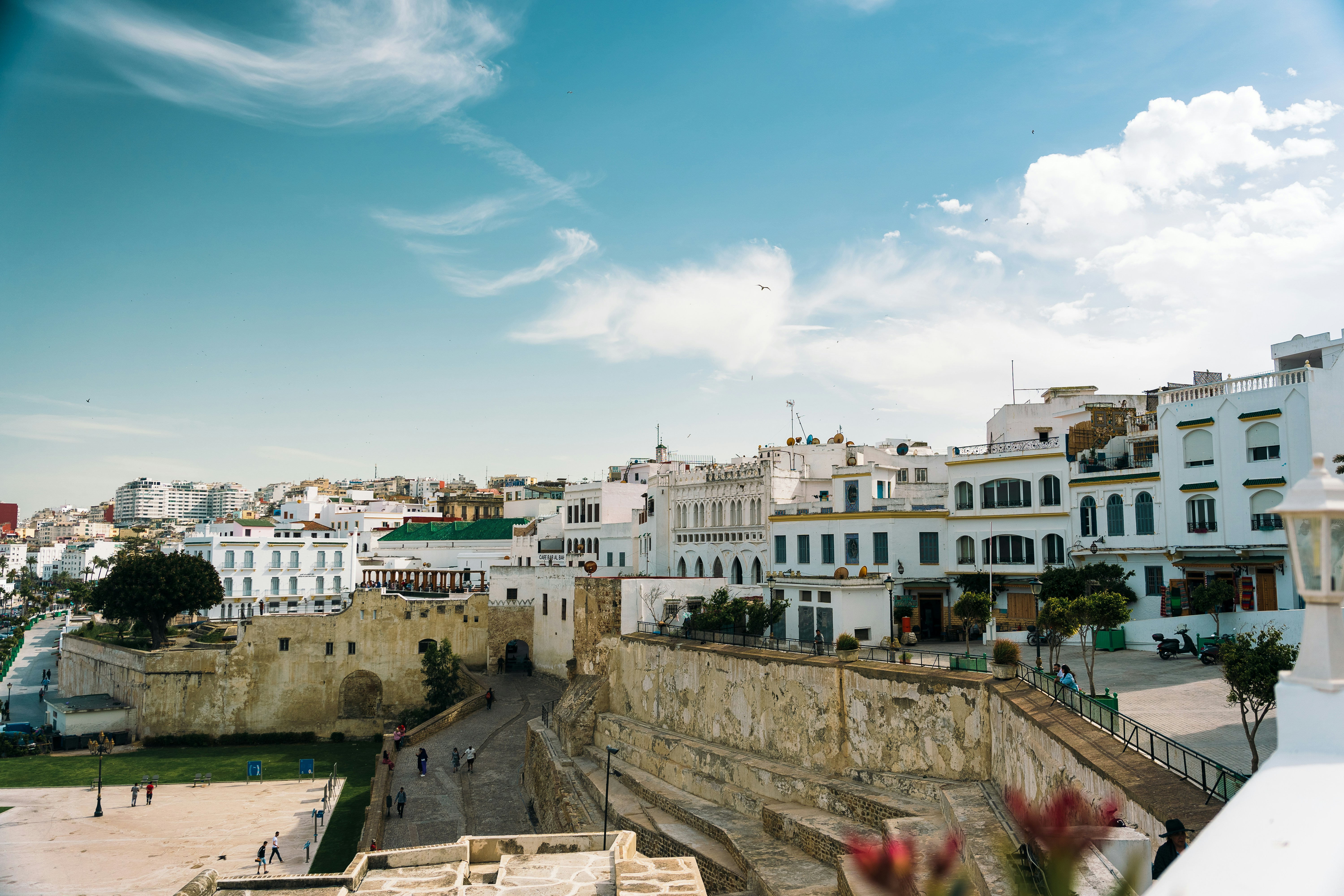 White buildings overlook a coastal city with blue sky.