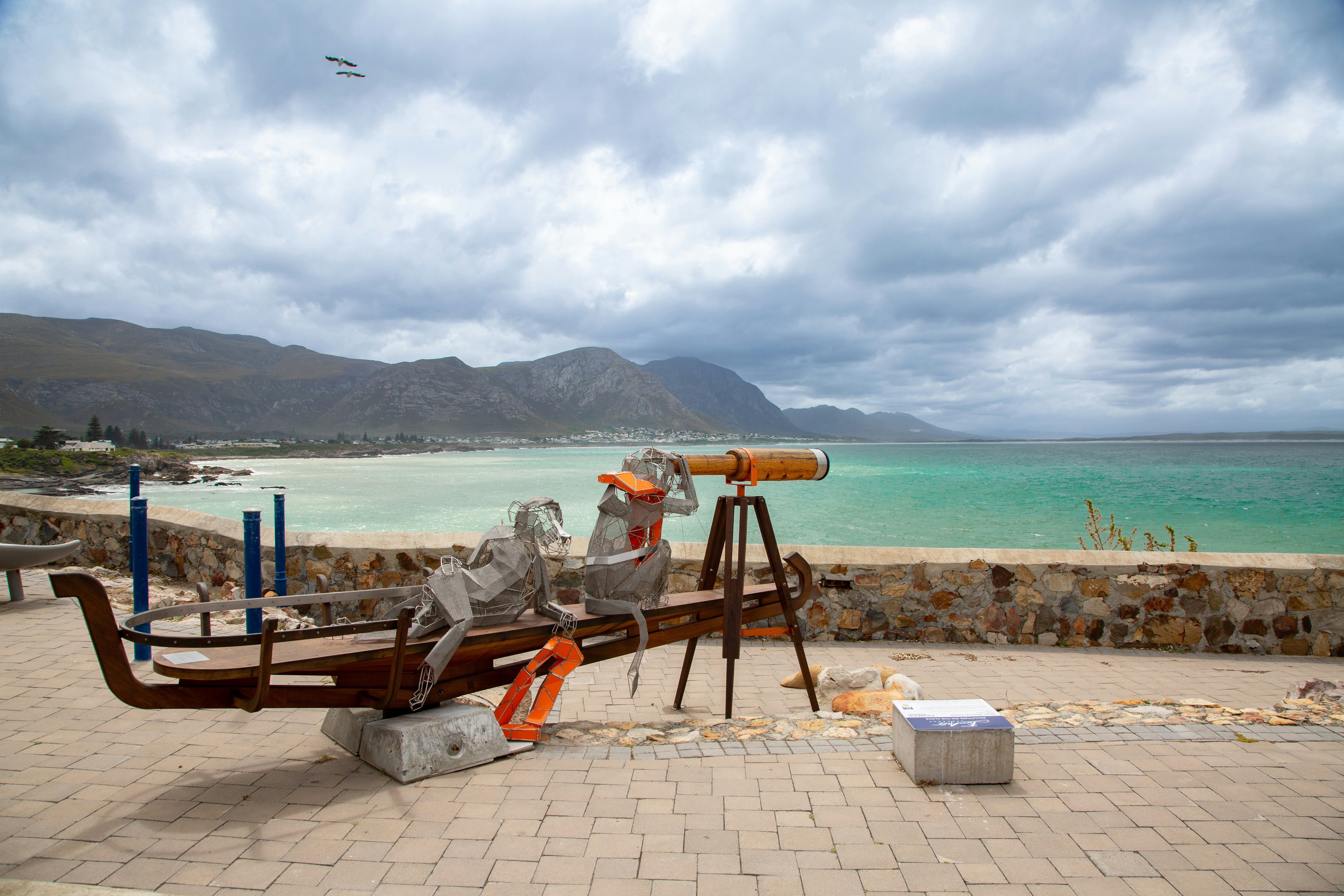 Sculpture of people looking through telescope at sea
