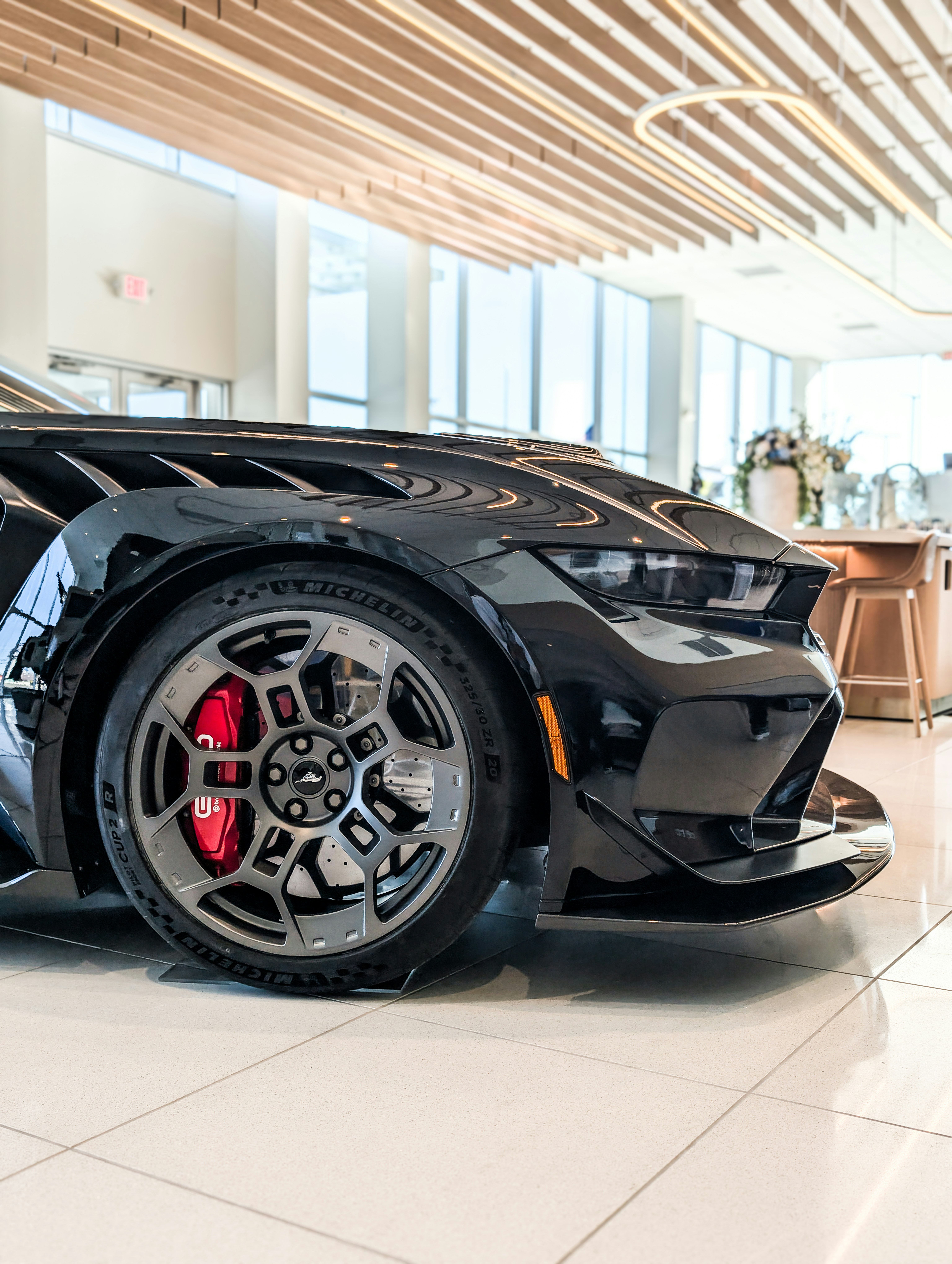 This front quarter view is pure automotive aggression! The massive 325-section tire, enormous red brakes, and functional fender vents create an incredibly powerful and technologically sophisticated visual statement of track-ready, high-performance design.