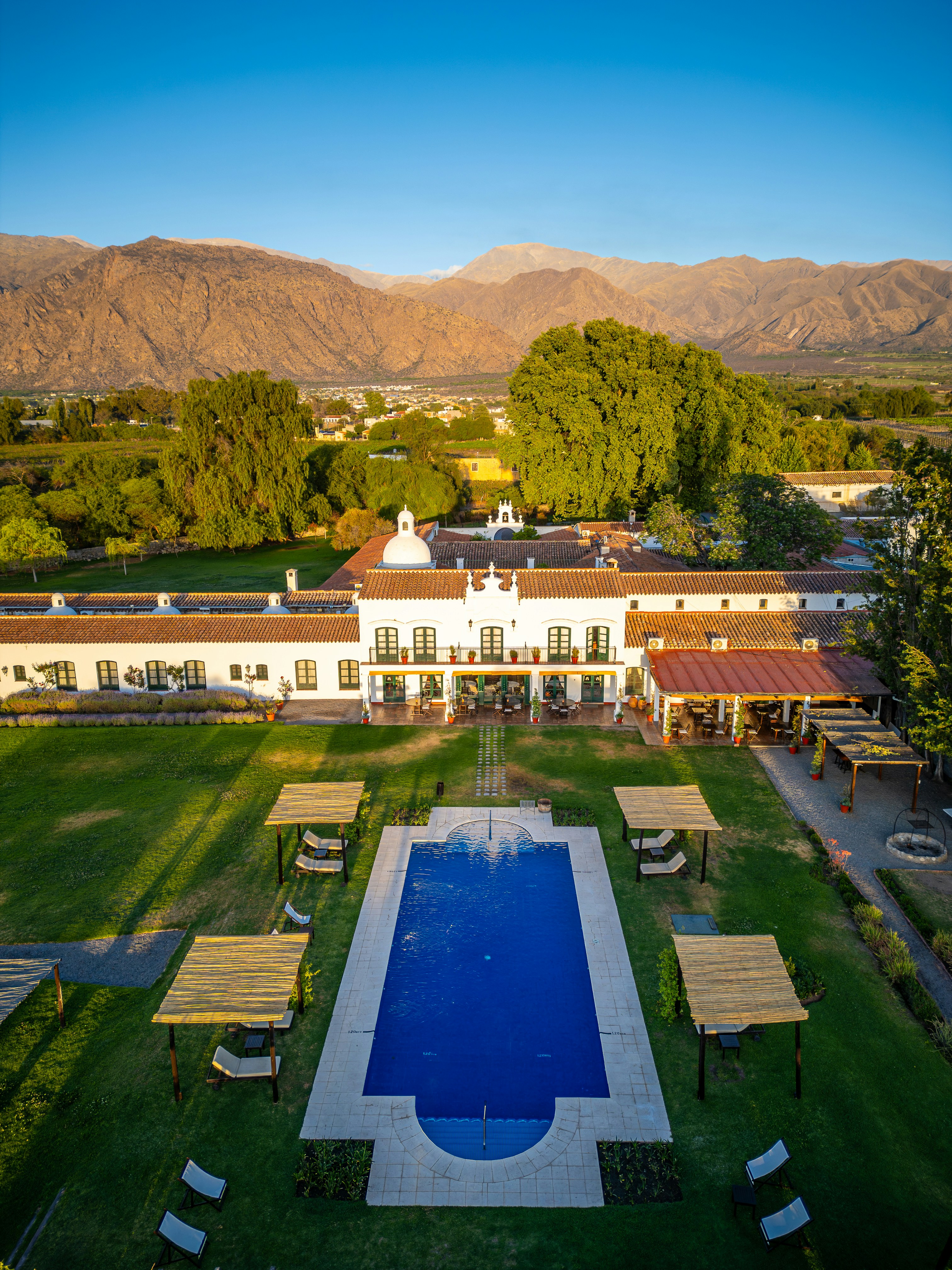Azure Oasis: Central Pool Aligns with a White Estate Under Rugged Mountain Backdrop