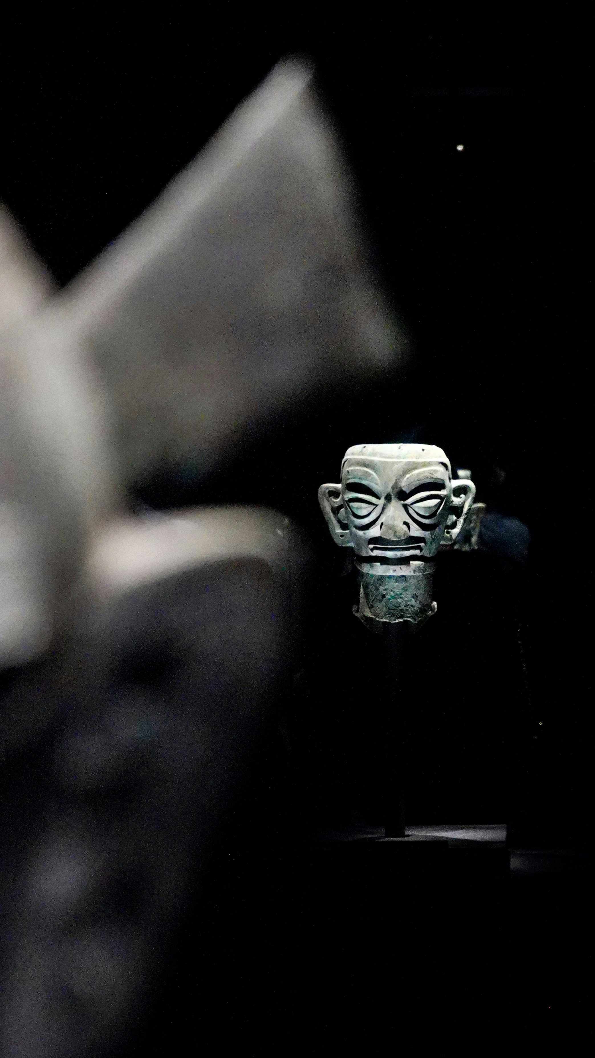 Midnight Gaze: A Weathered Tiki Mask Emerges from Velvet Darkness