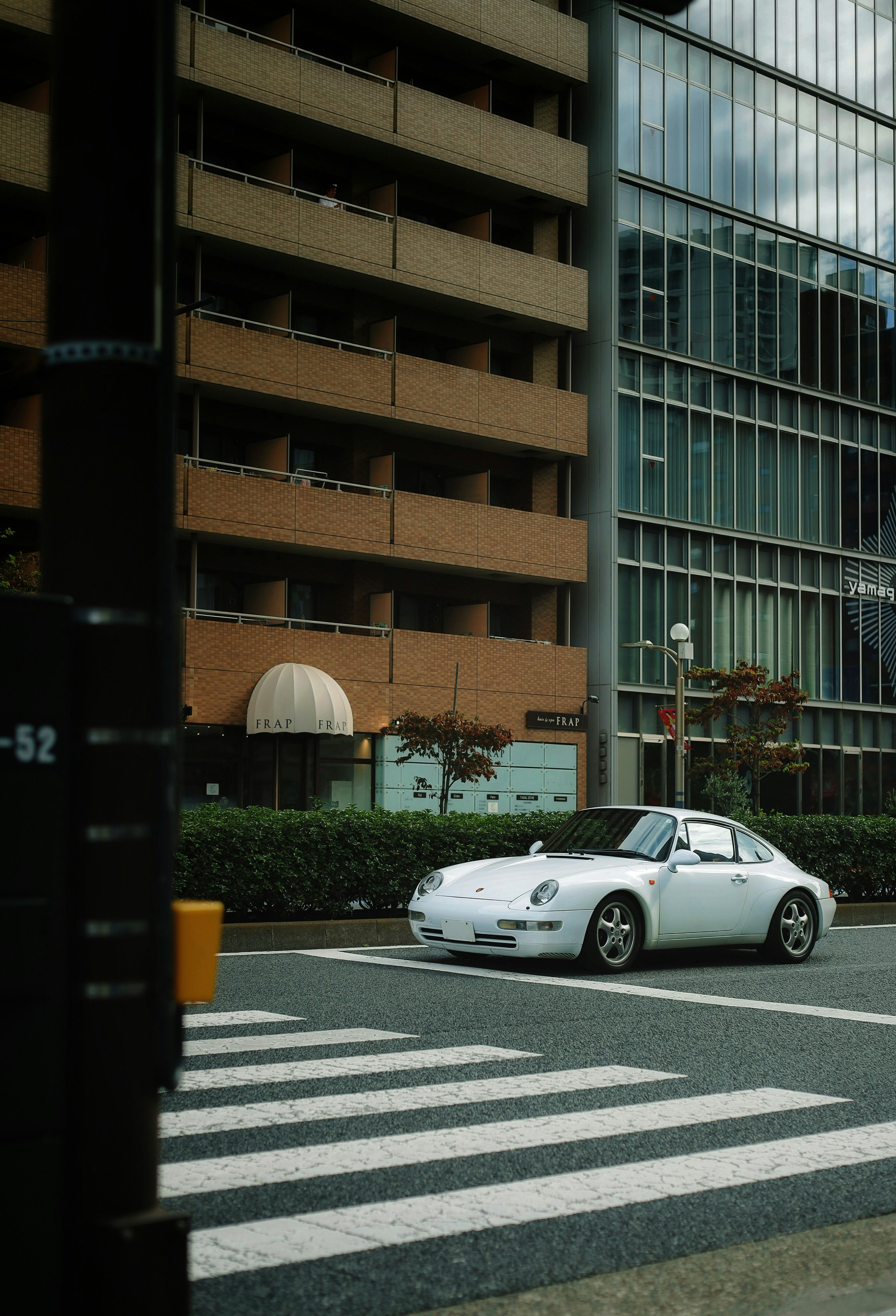 Chrome-White Porsche on a City Block Between Brick and Glass