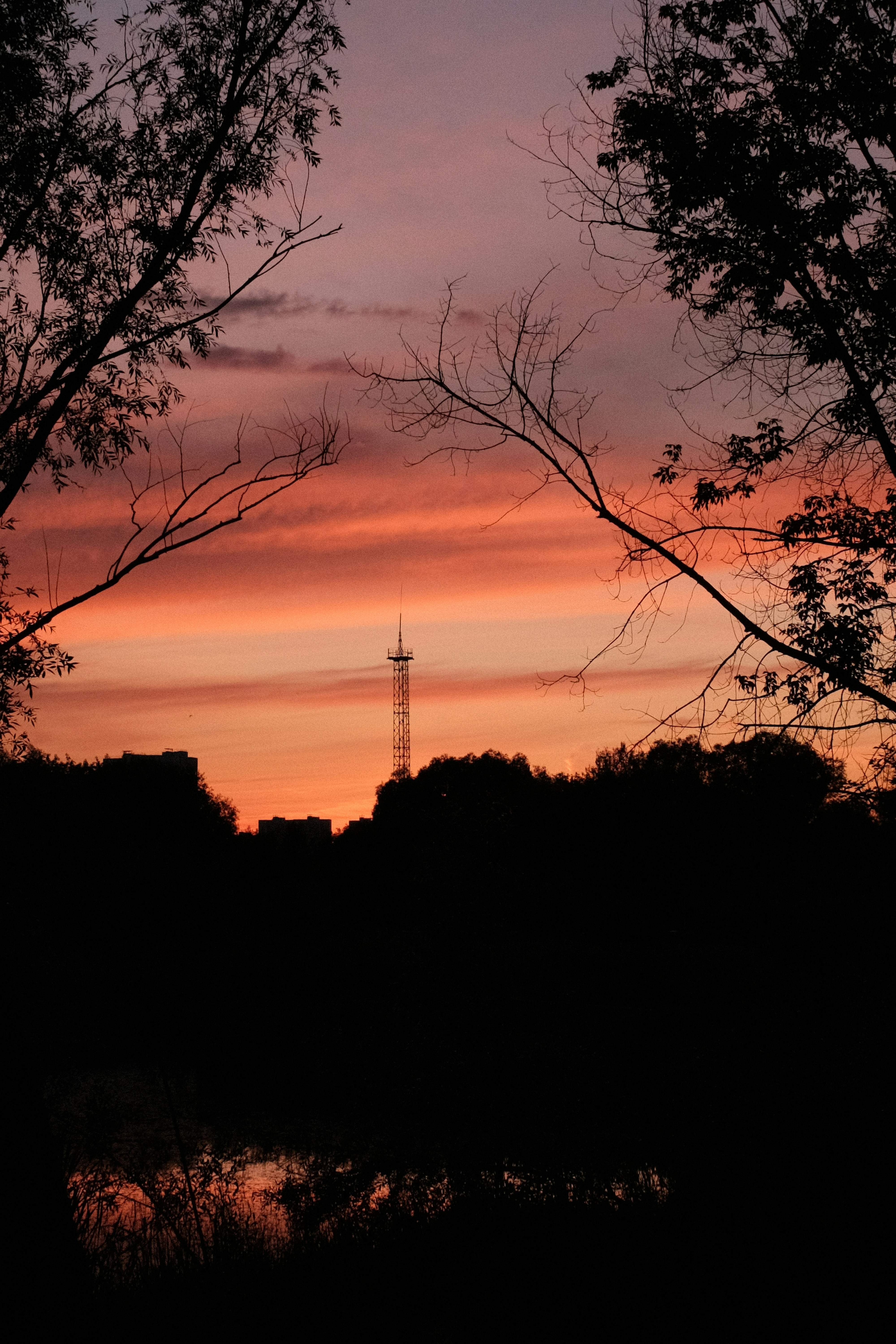 Crimson Dusk: Silhouettes Framing a Lone Tower at Sunset