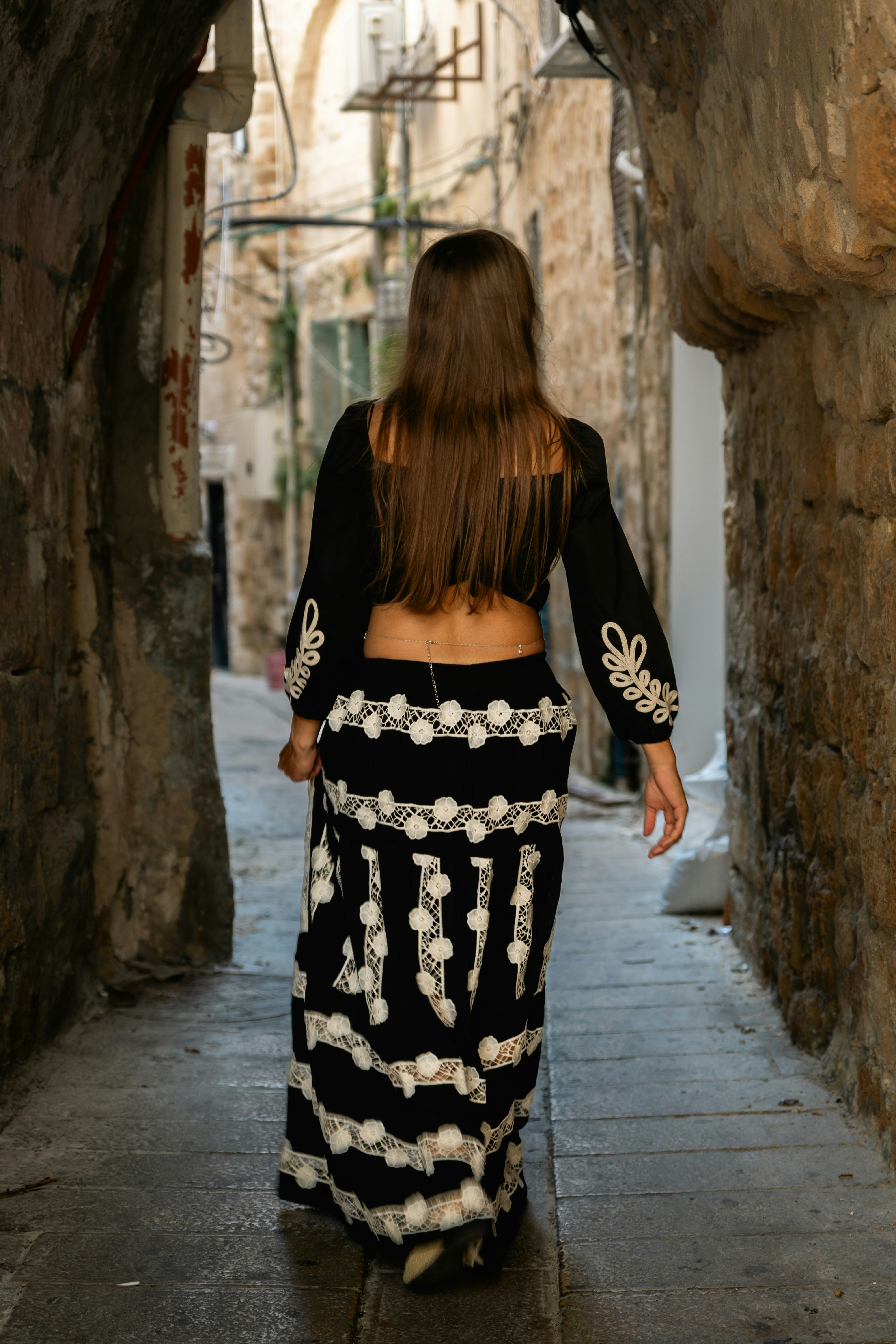 Back Turn in a Narrow Stone Alley: Embroidered Black and White in Motion