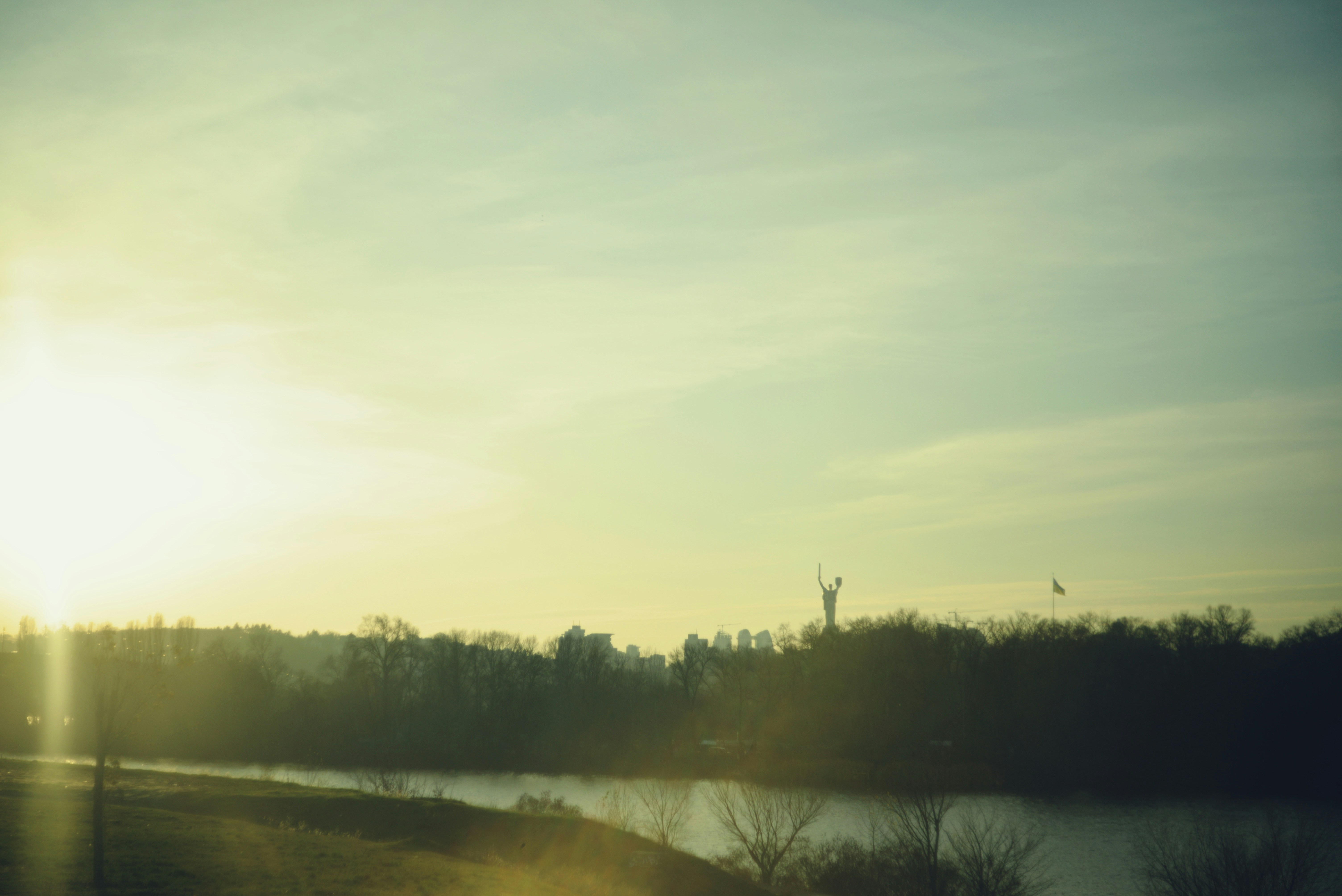 Golden Haze at the Quiet Lake: Dawn Over a Distant Tree-Line