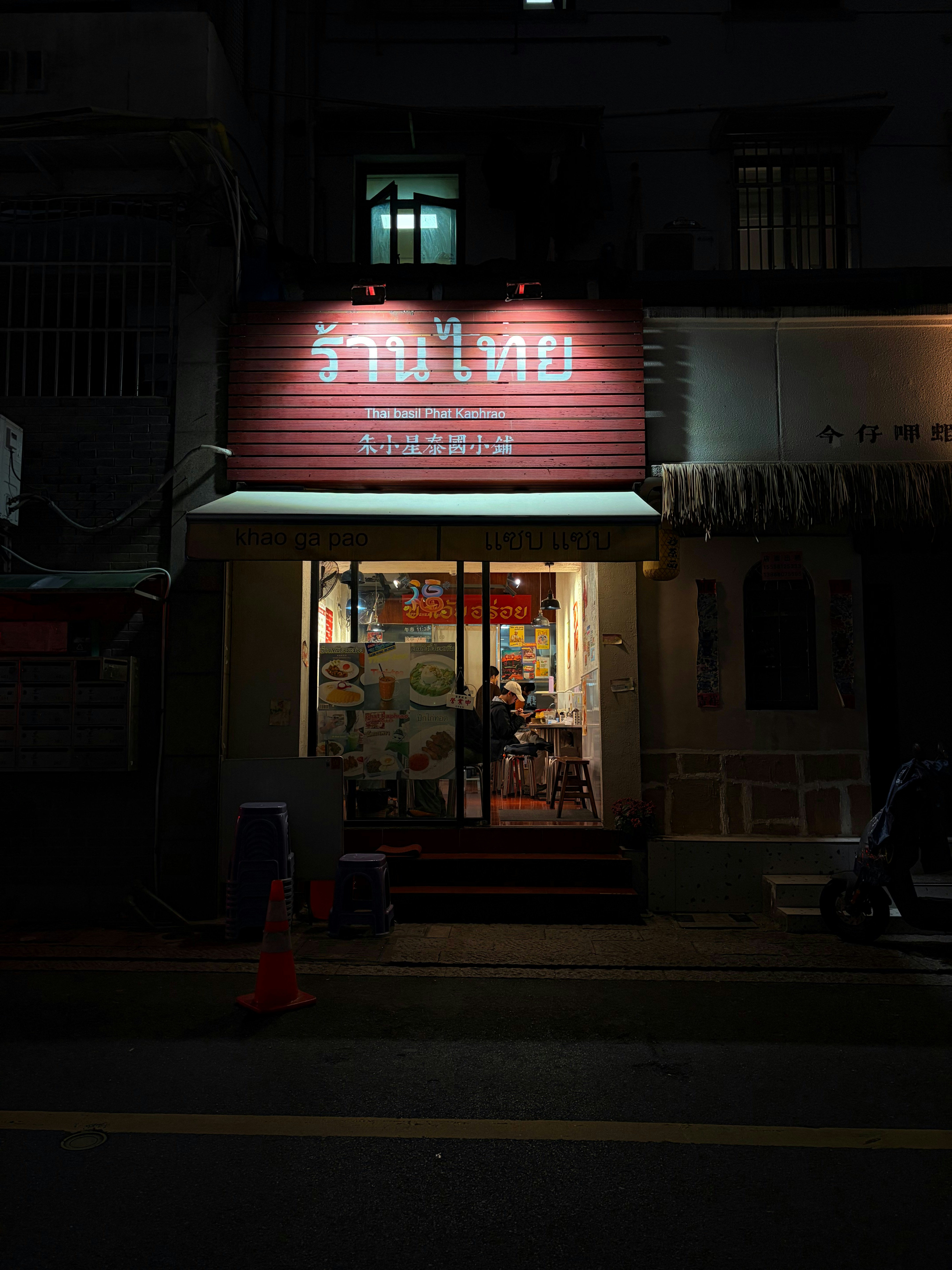 Thai restaurant storefront at night illuminated by streetlights