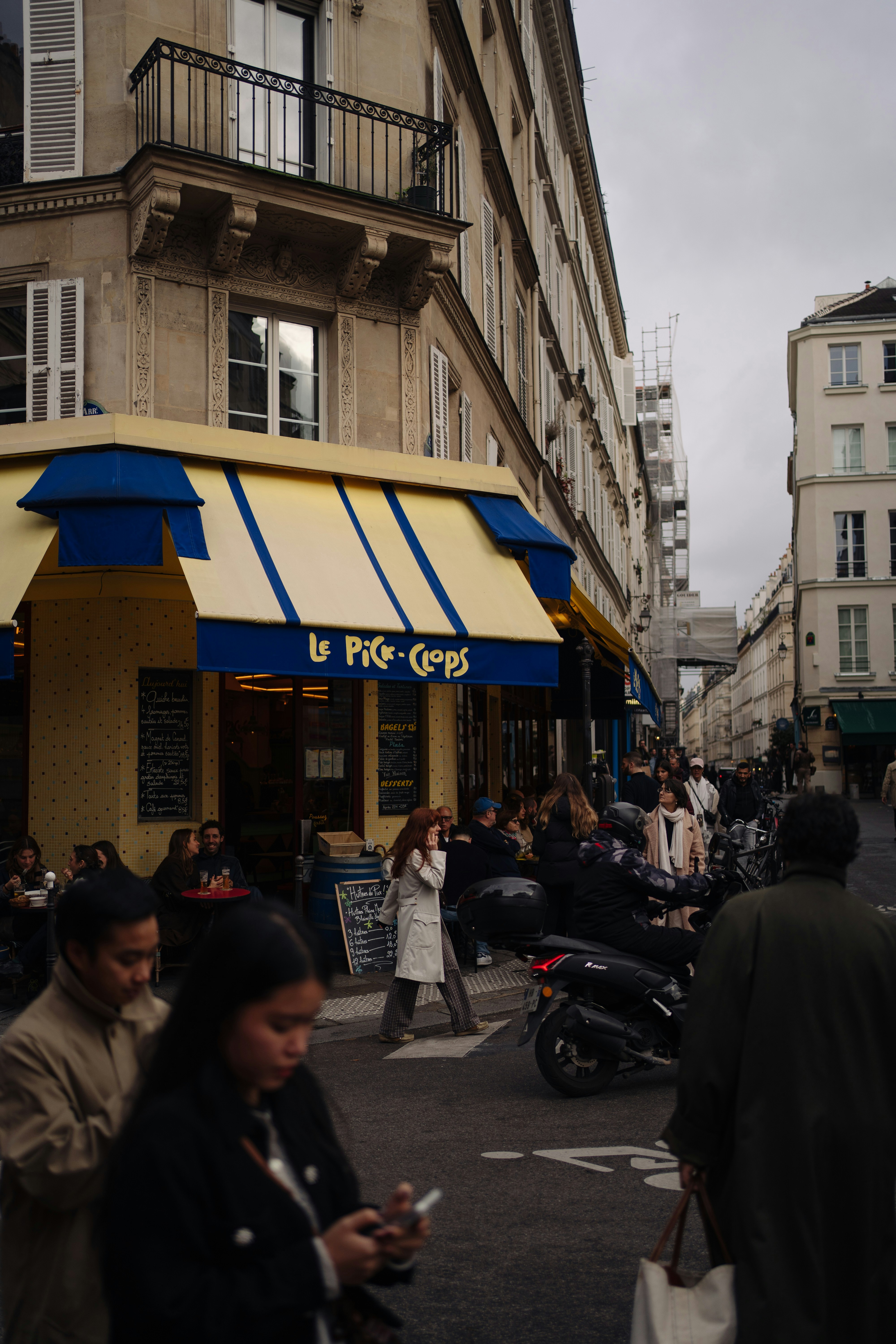 Parisian Café Corner: Blue and Yellow Canopies Amid a Lively Street