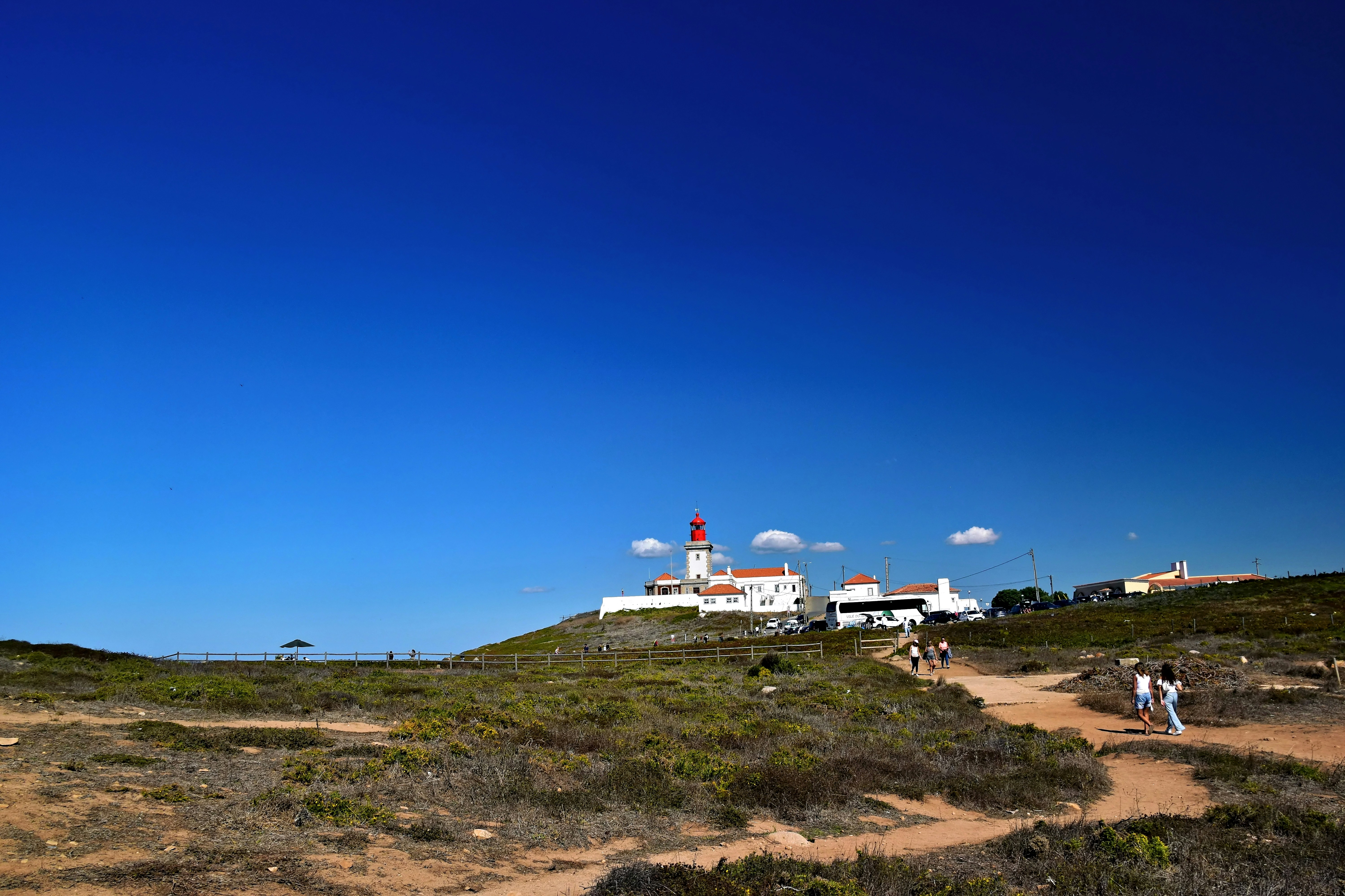 White Lighthouse on a Wind-Swept Hill Under a Pristine Blue Sky