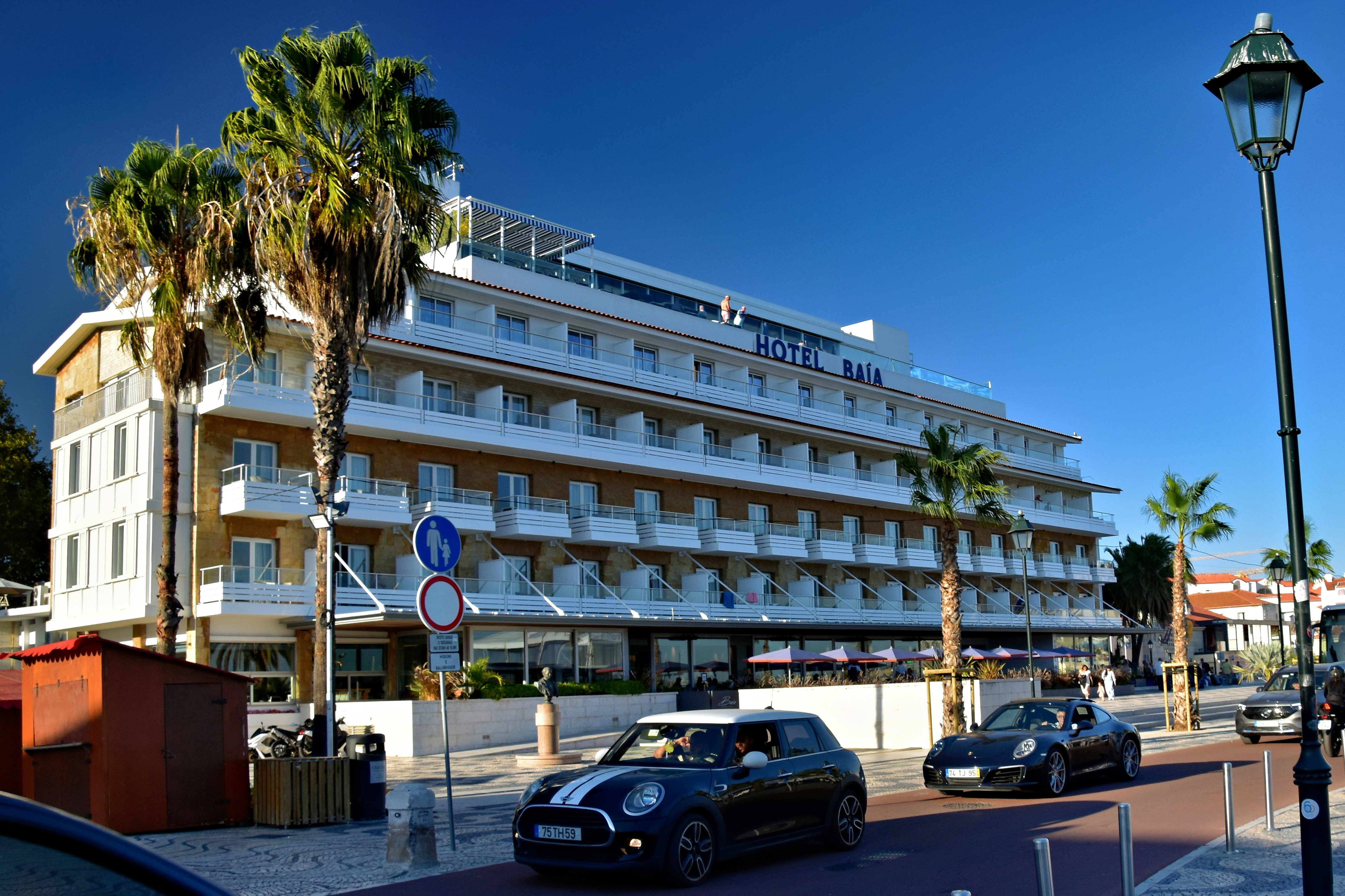 Baía Hotel Facade on a Palm-Fringed Promenade Under a Bright Blue Sky