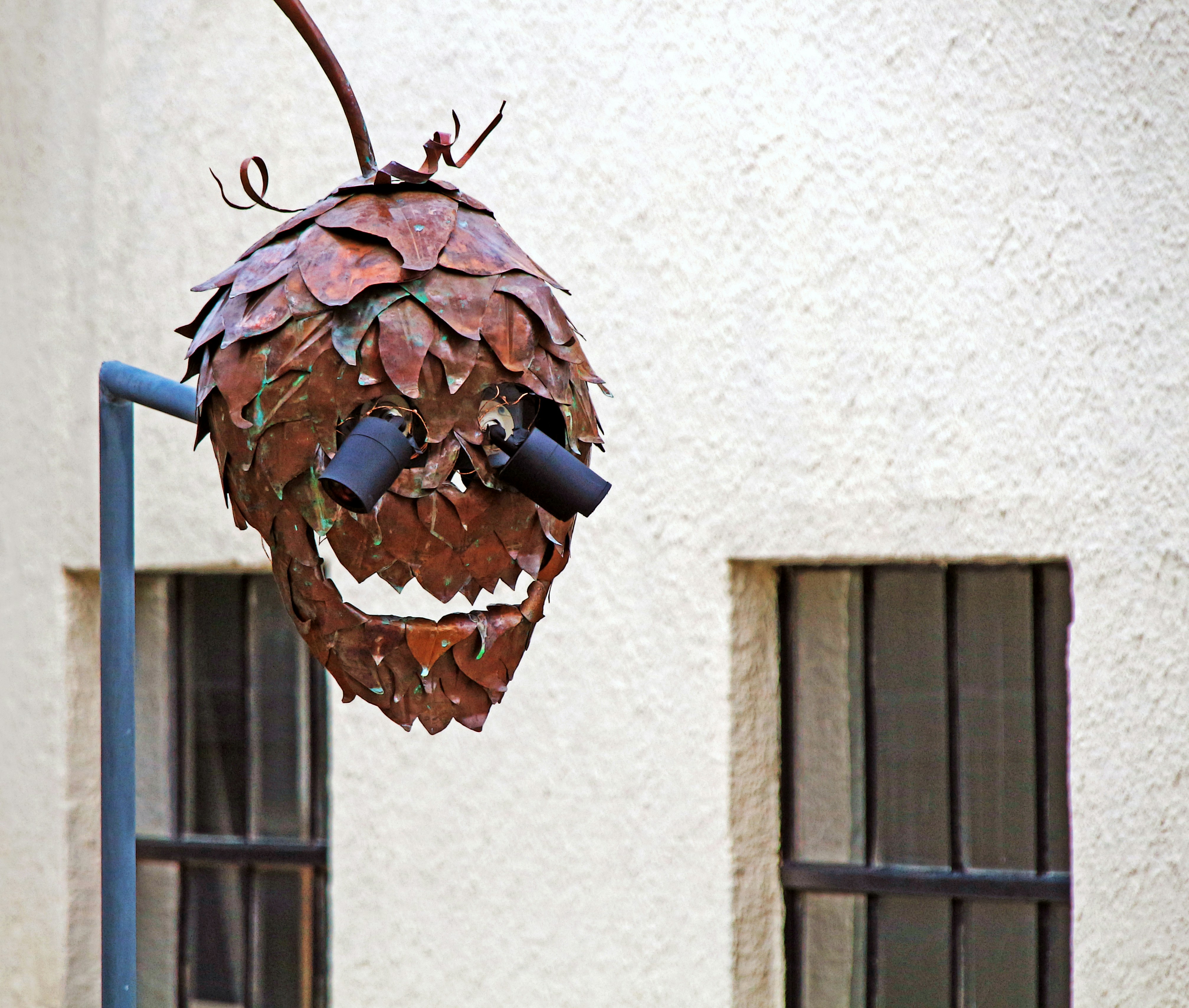 Leaf-Armor Smile: A Rusted Mask on a Sunlit Wall