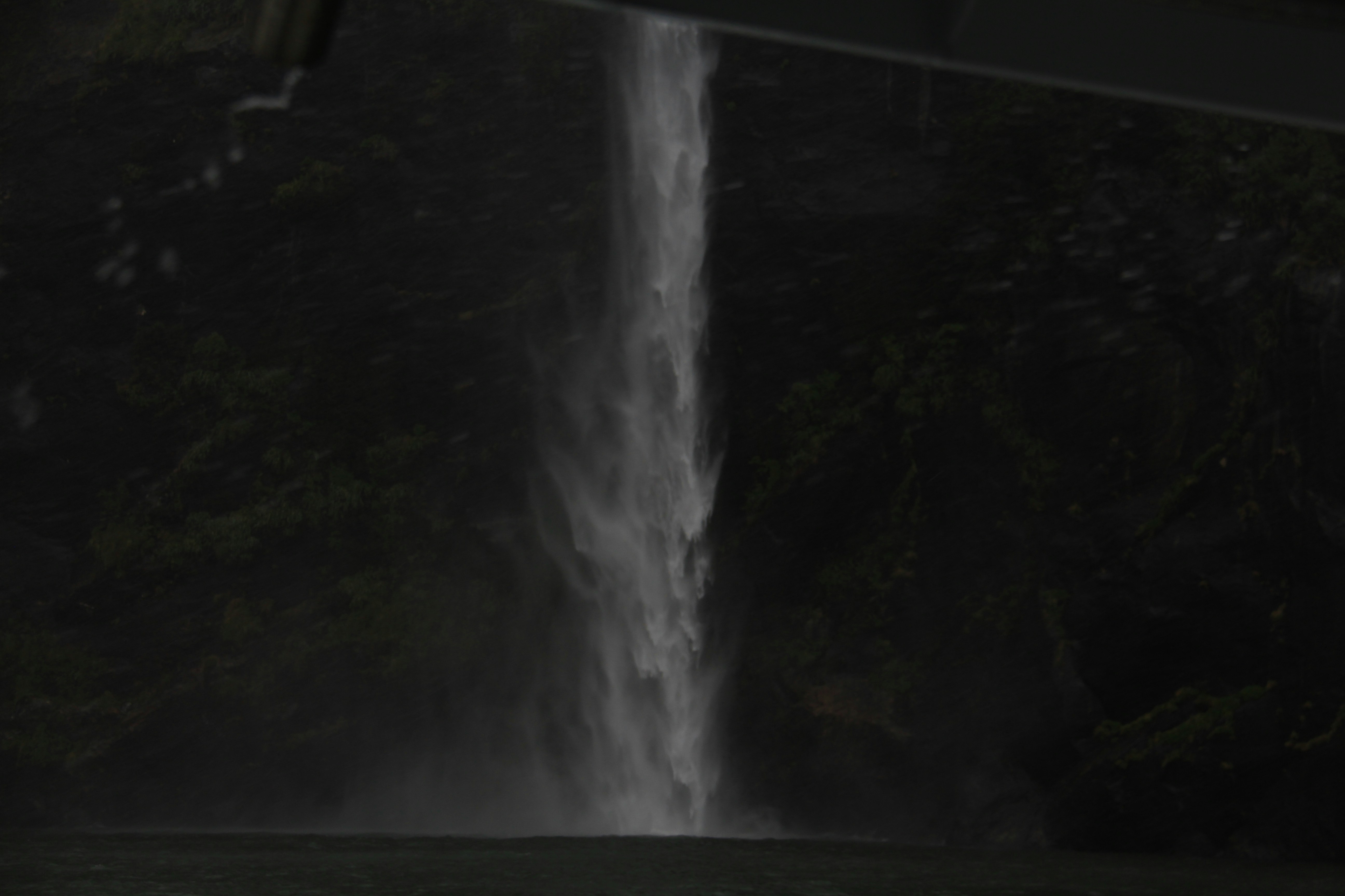 Midnight Cascade: A Narrow Waterfall Piercing the Night in a Shadowed Forest