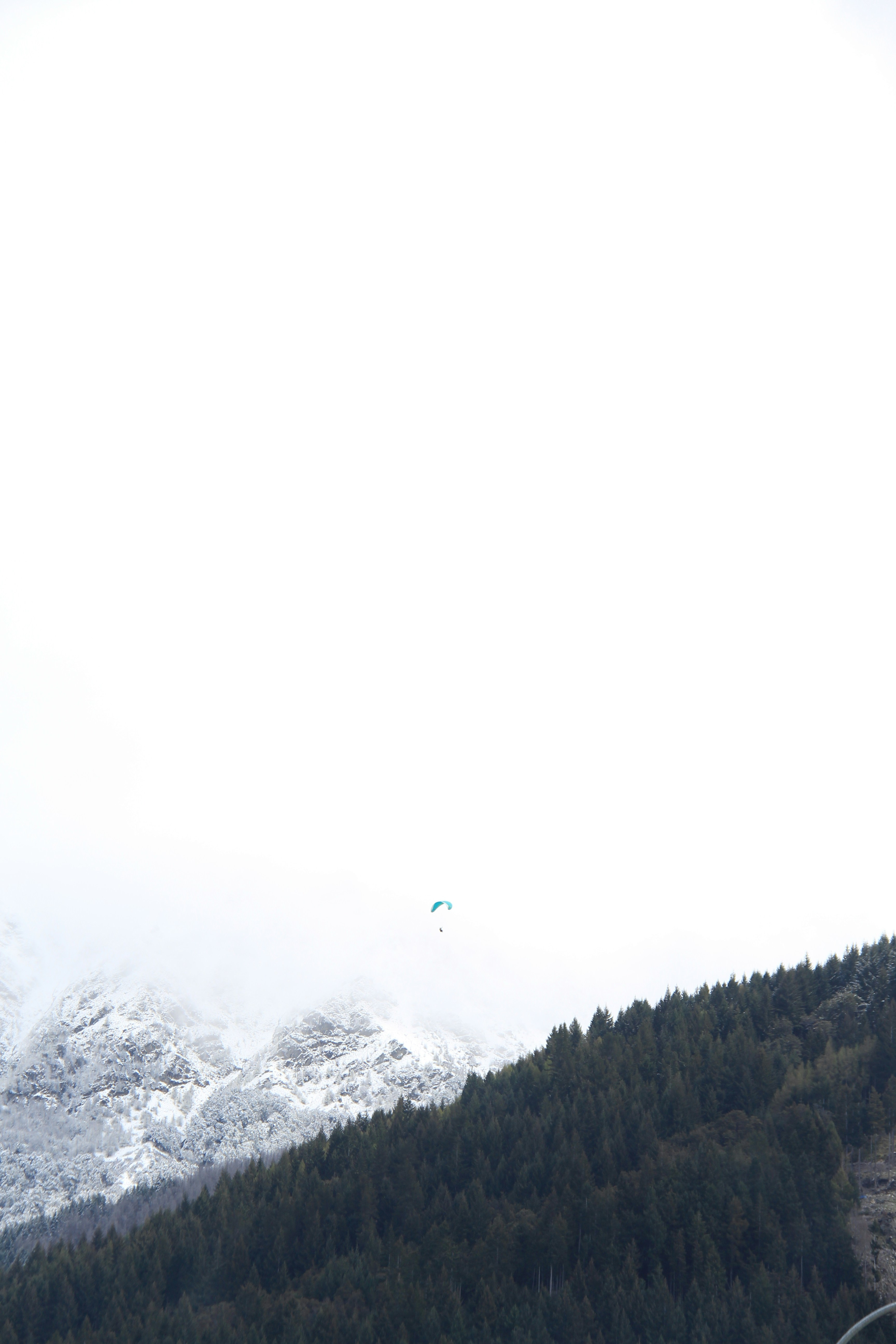 Blue Paraglider Above Snow-Dusted Peaks
