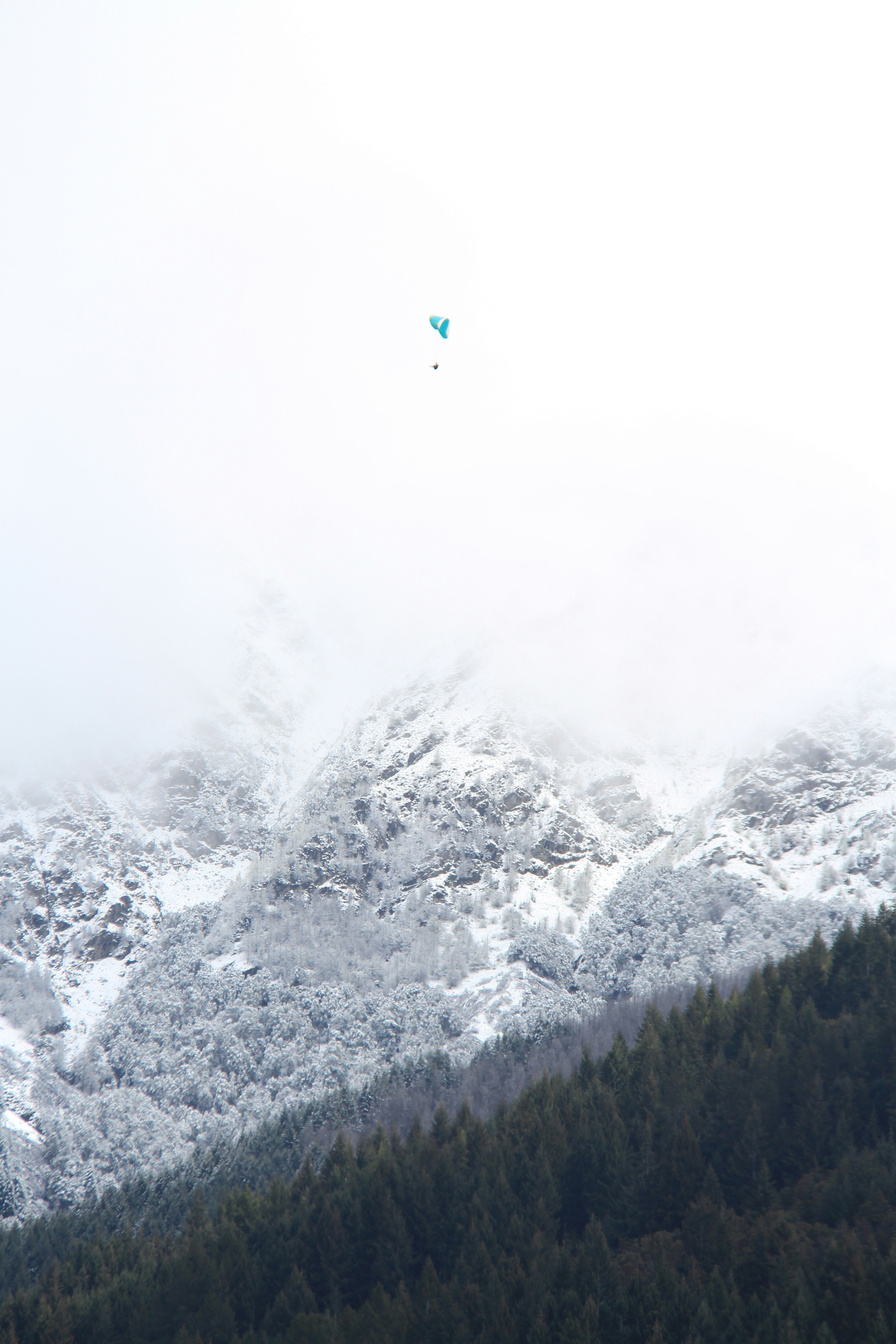 Blue Paraglider Over Snow-Dusted Alpine Peaks