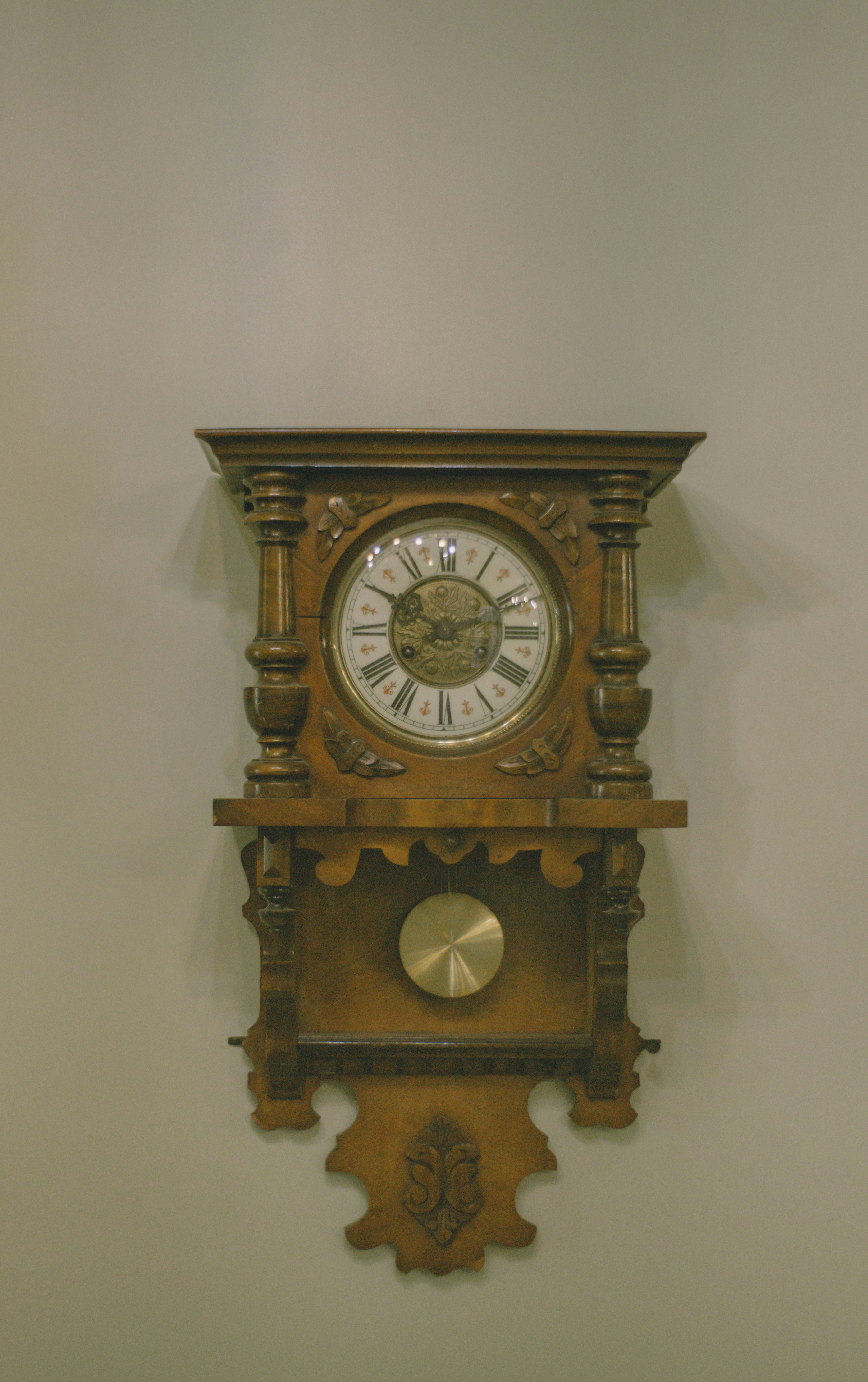 Ornate Timekeeper: A Vintage Carved Wall Clock Adorning a Pale Wall