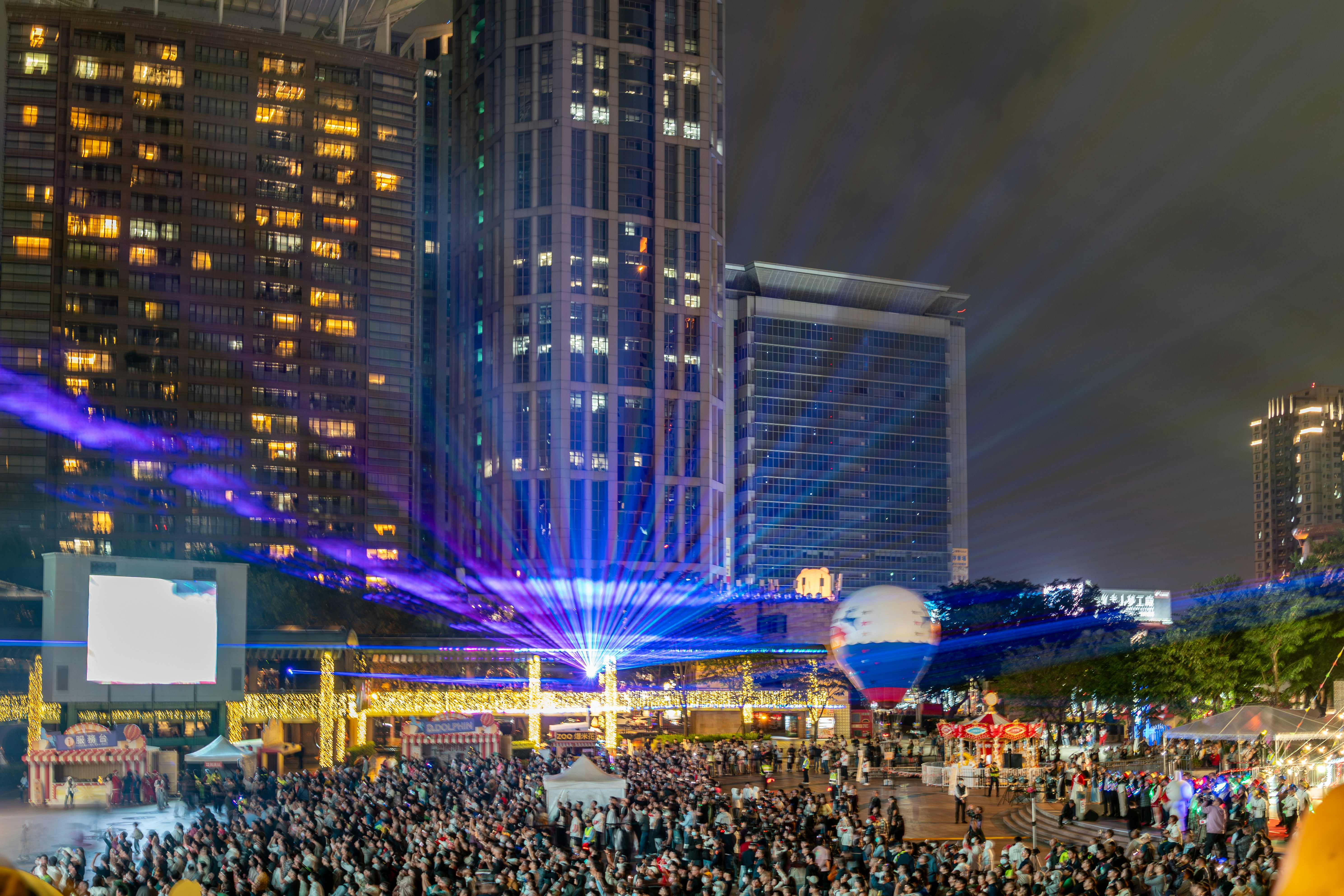 Blue Cascade Over a City Plaza: Neon Night, Packed Crowd
