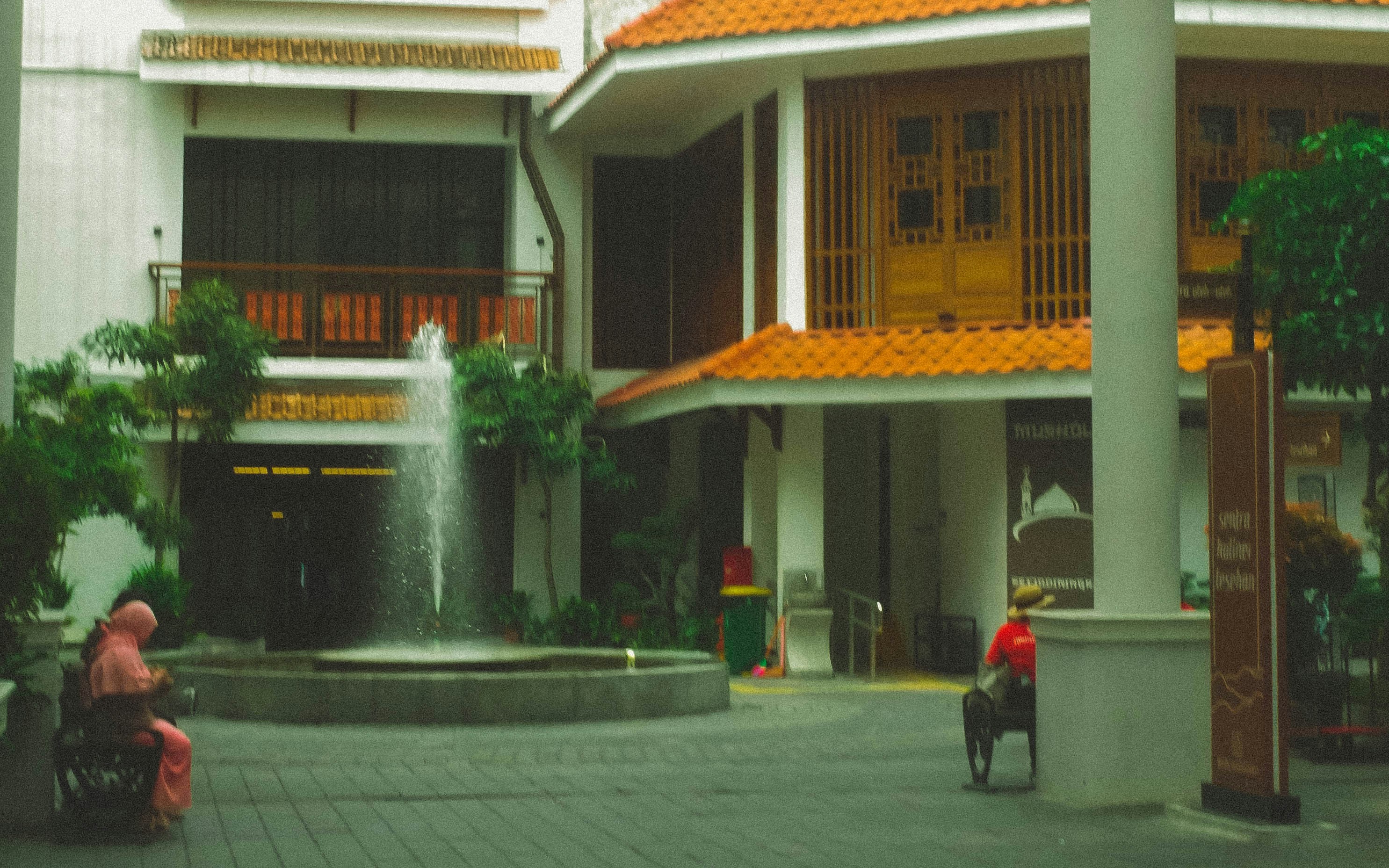 Fountain in front of a building with people.
