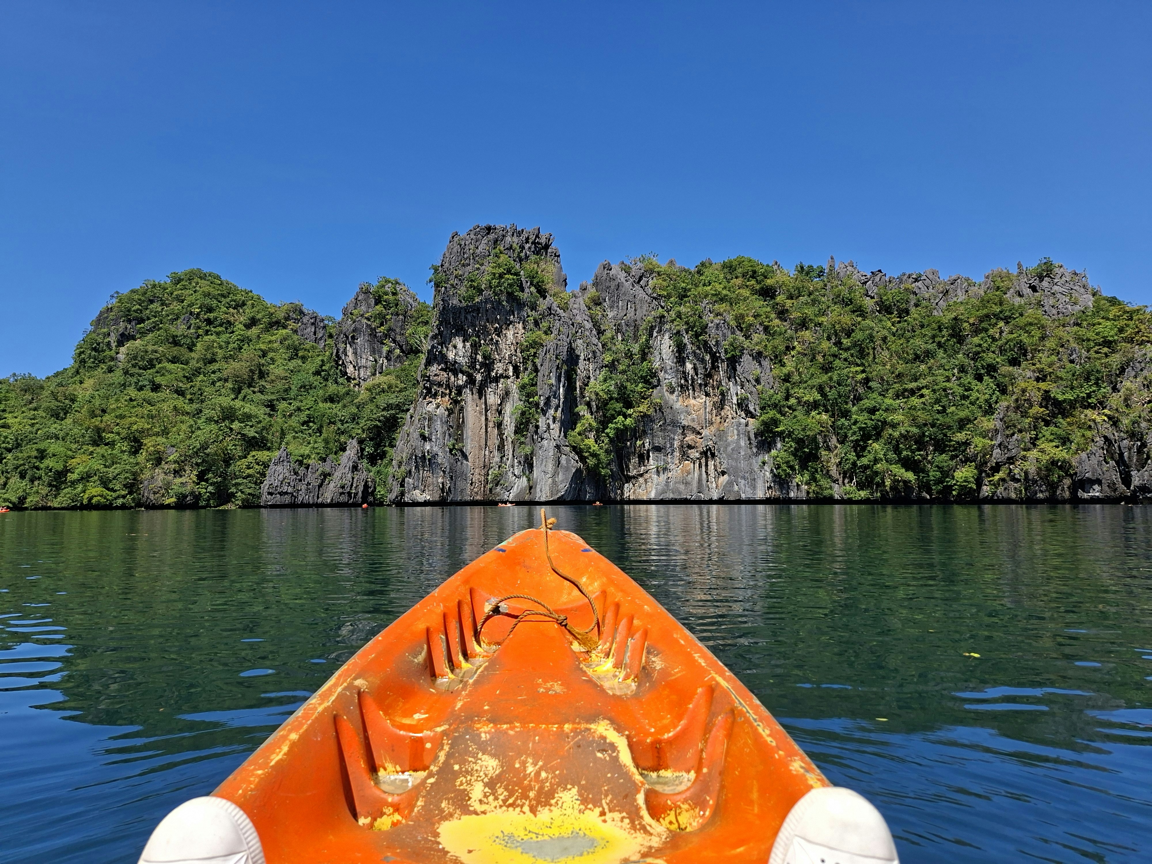 Kayaking towards a lush green island with rocky cliffs.