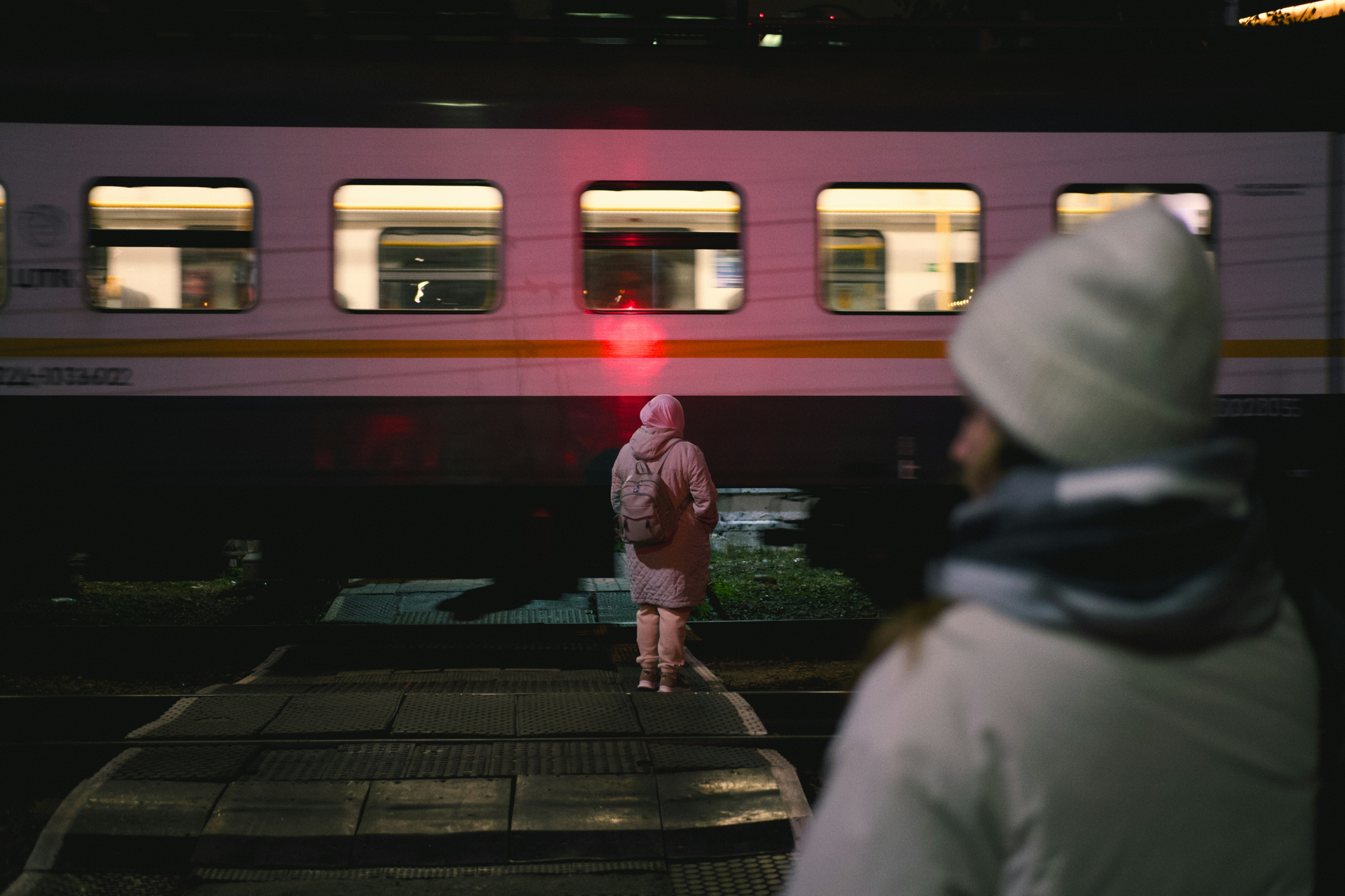 Midnight Platform Stillness: A lone traveler watches a passing train