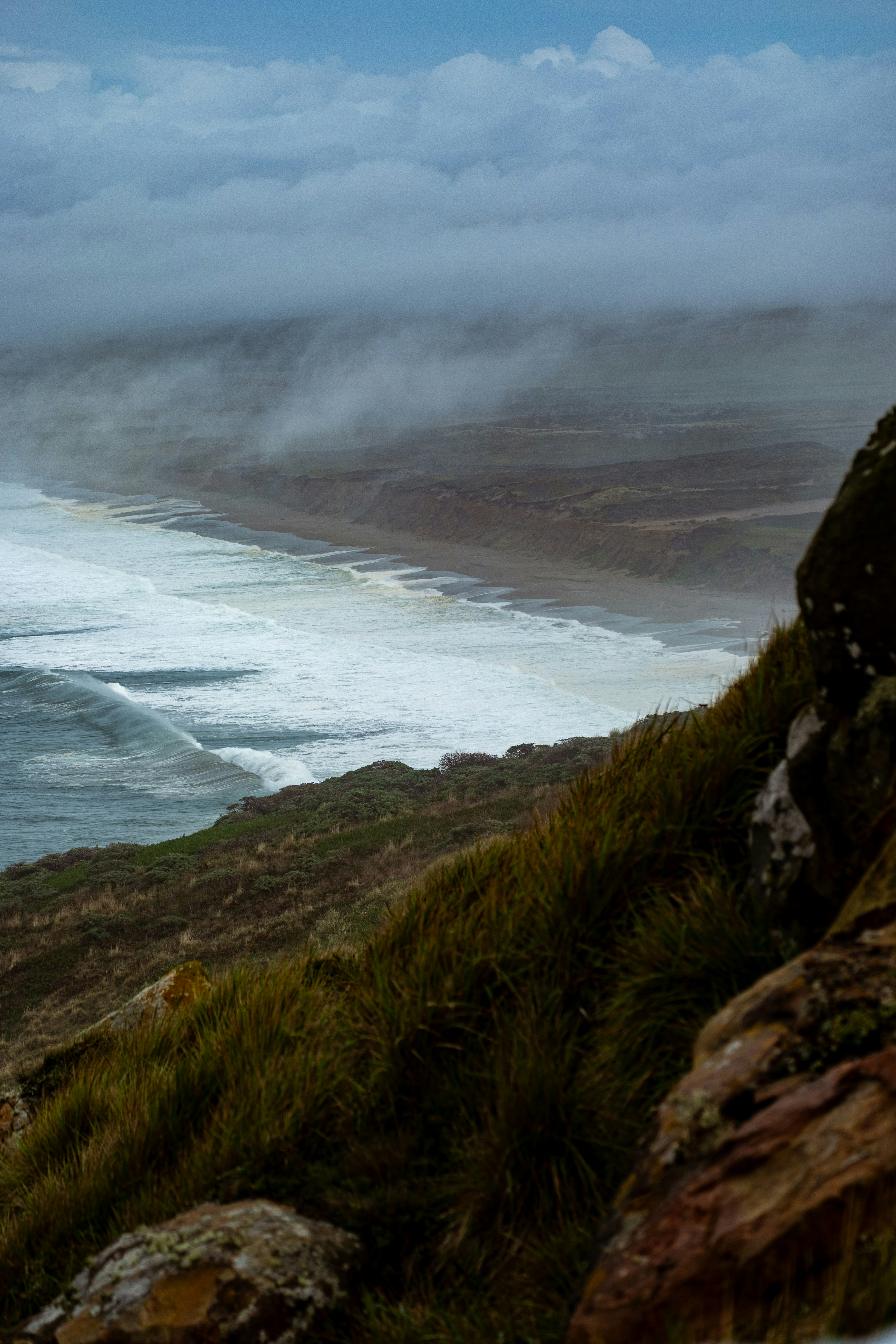 Misty ocean waves crash on a rugged coastline.
