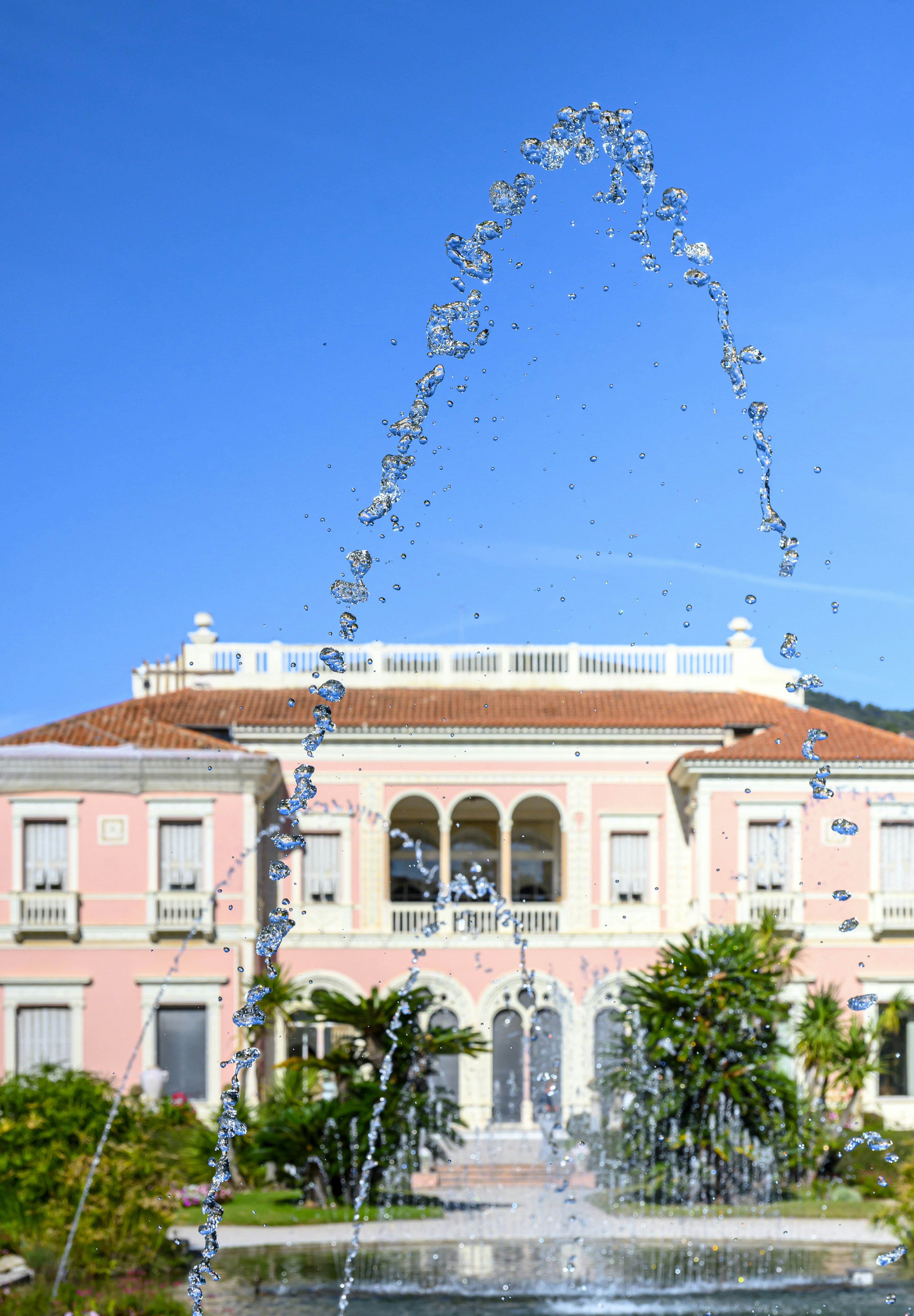 Arc of Water Over a Pastel Villa Courtyard