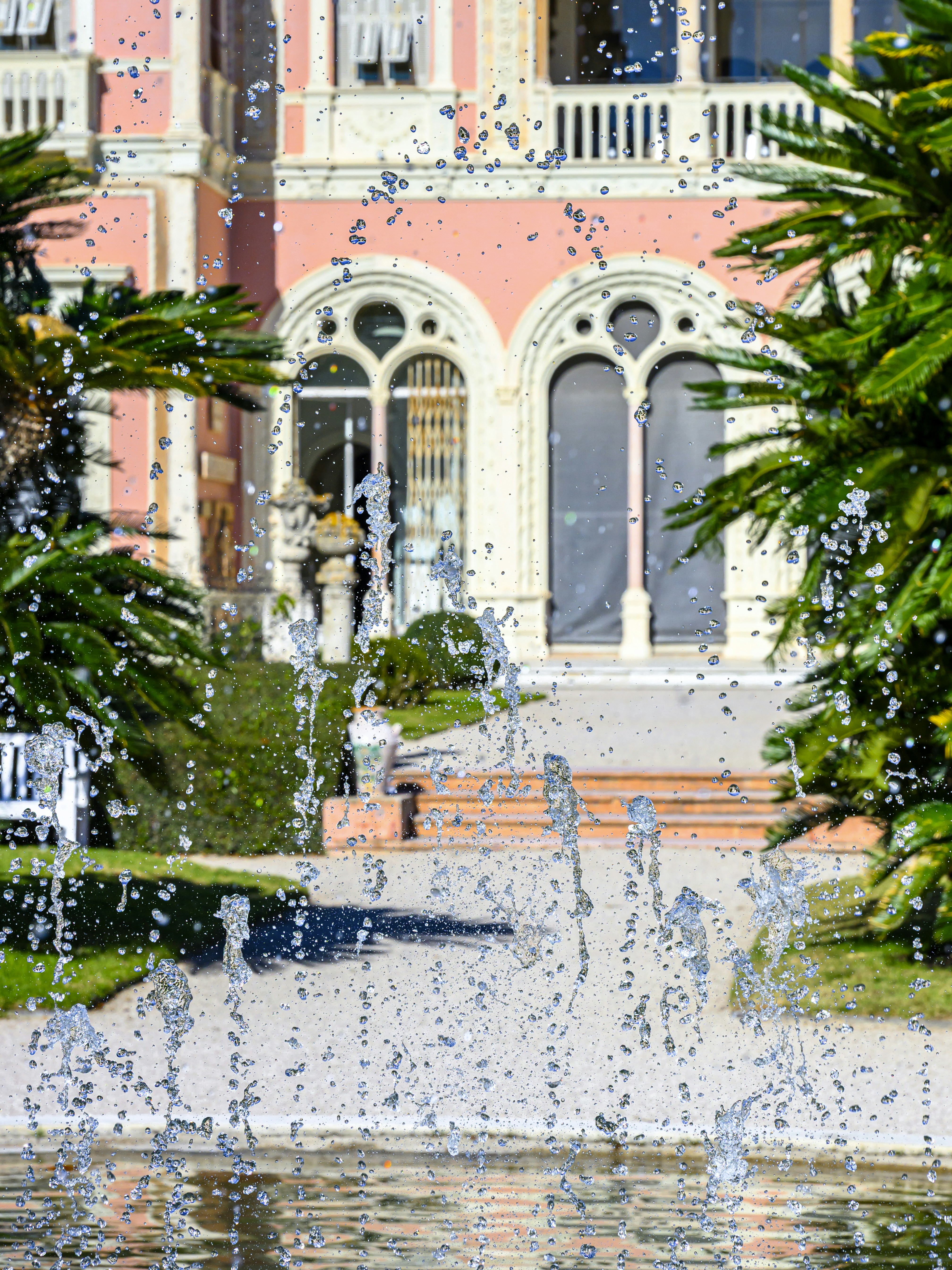 Pastel Courtyard: Fountain Spray Framing a Pink Villa