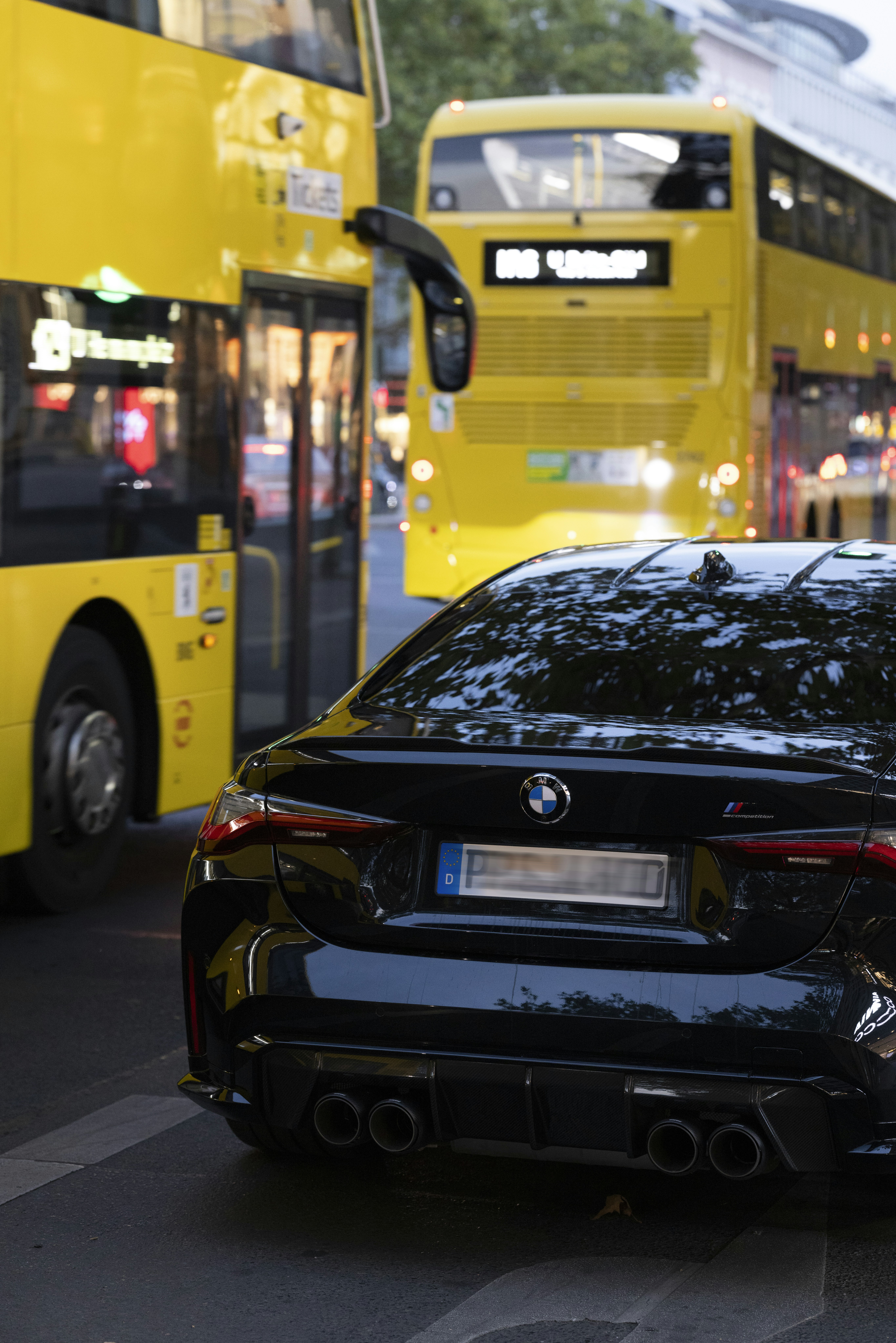 Rear-View Duel: A BMW M Anchored by Yellow City Buses