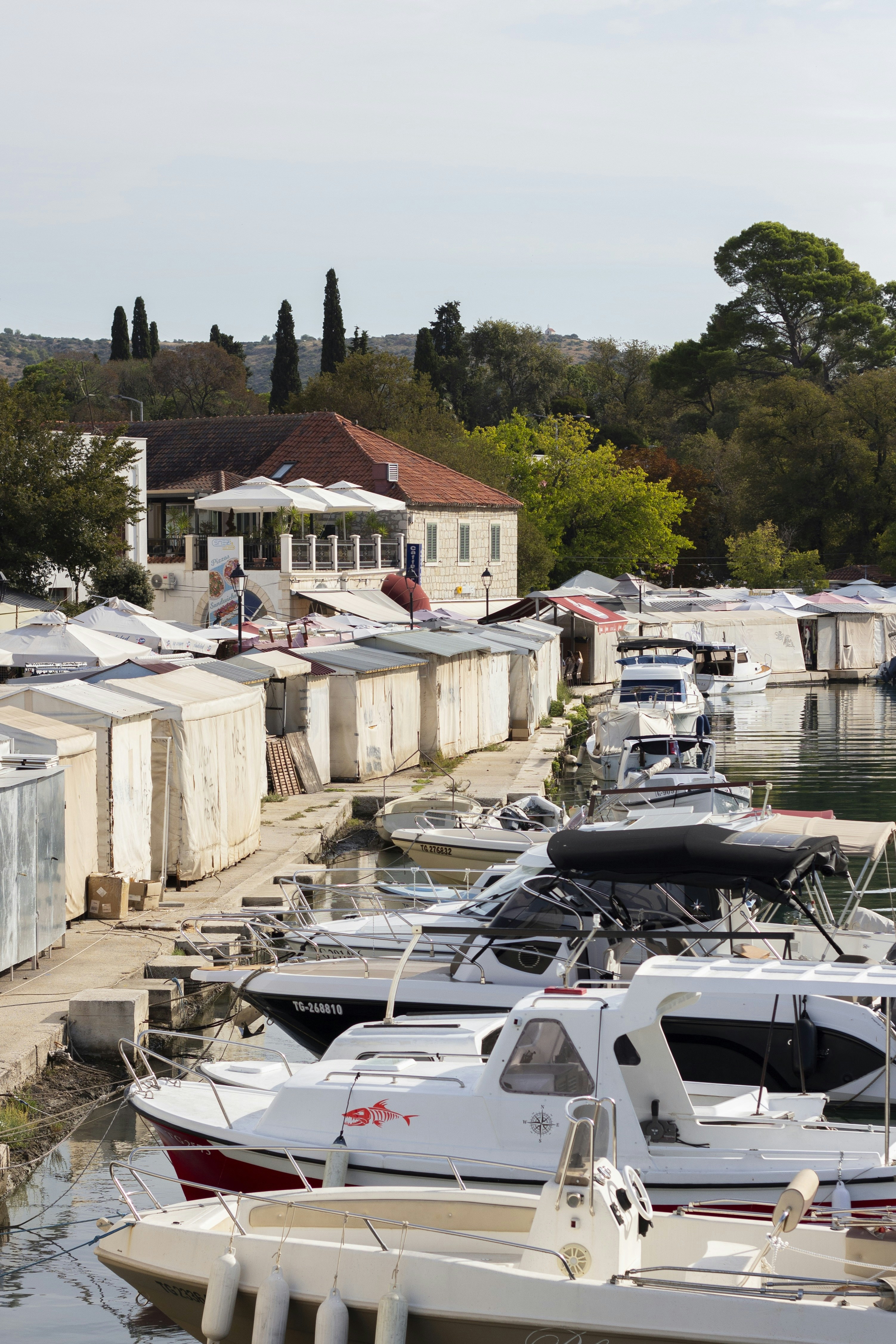 Quayline Palette: Boats, White Huts, and a Red-Roofed Retreat in Sunlit Calm