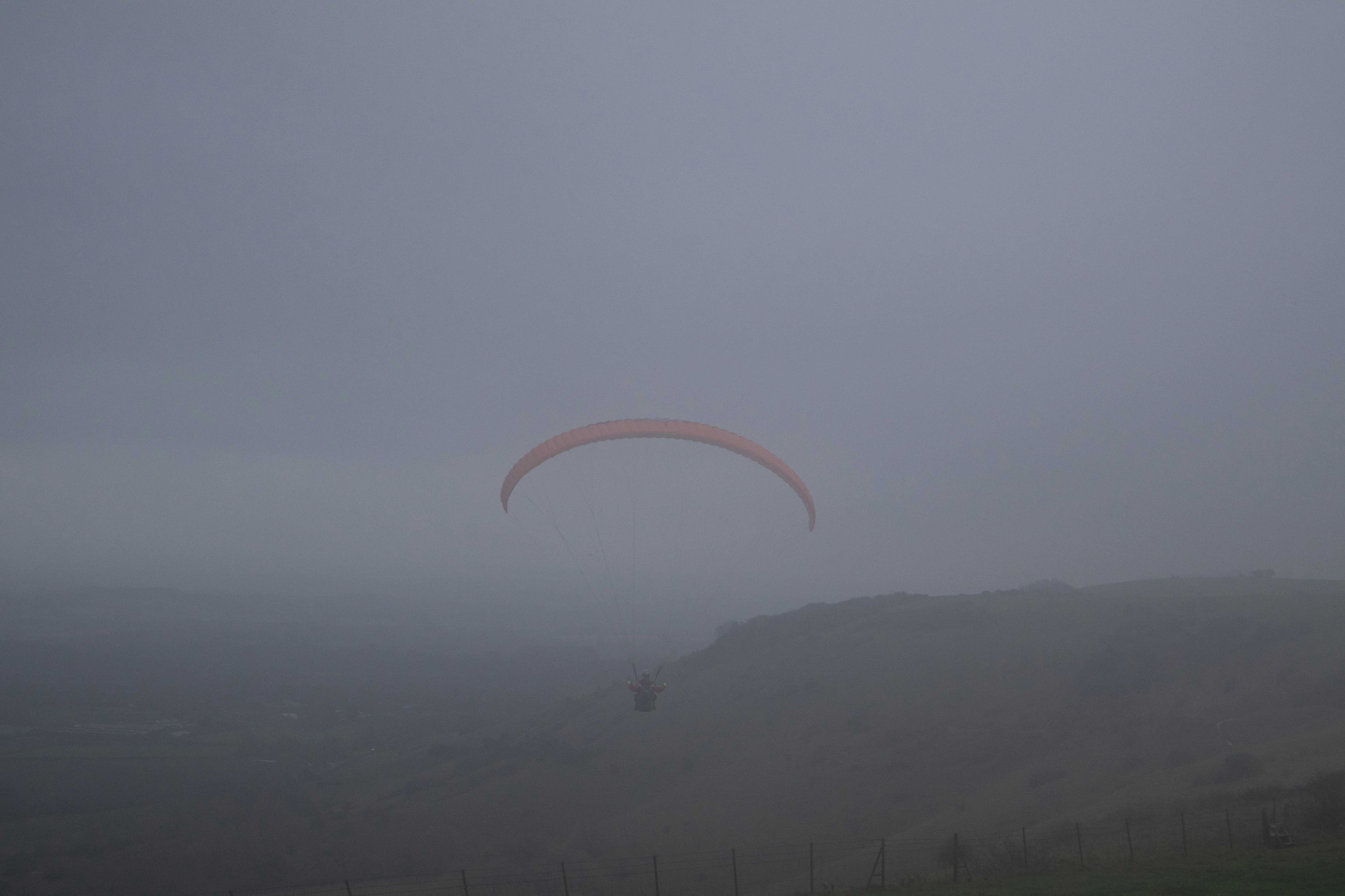 Crimson Arc Over a Mist-Wedged Coast