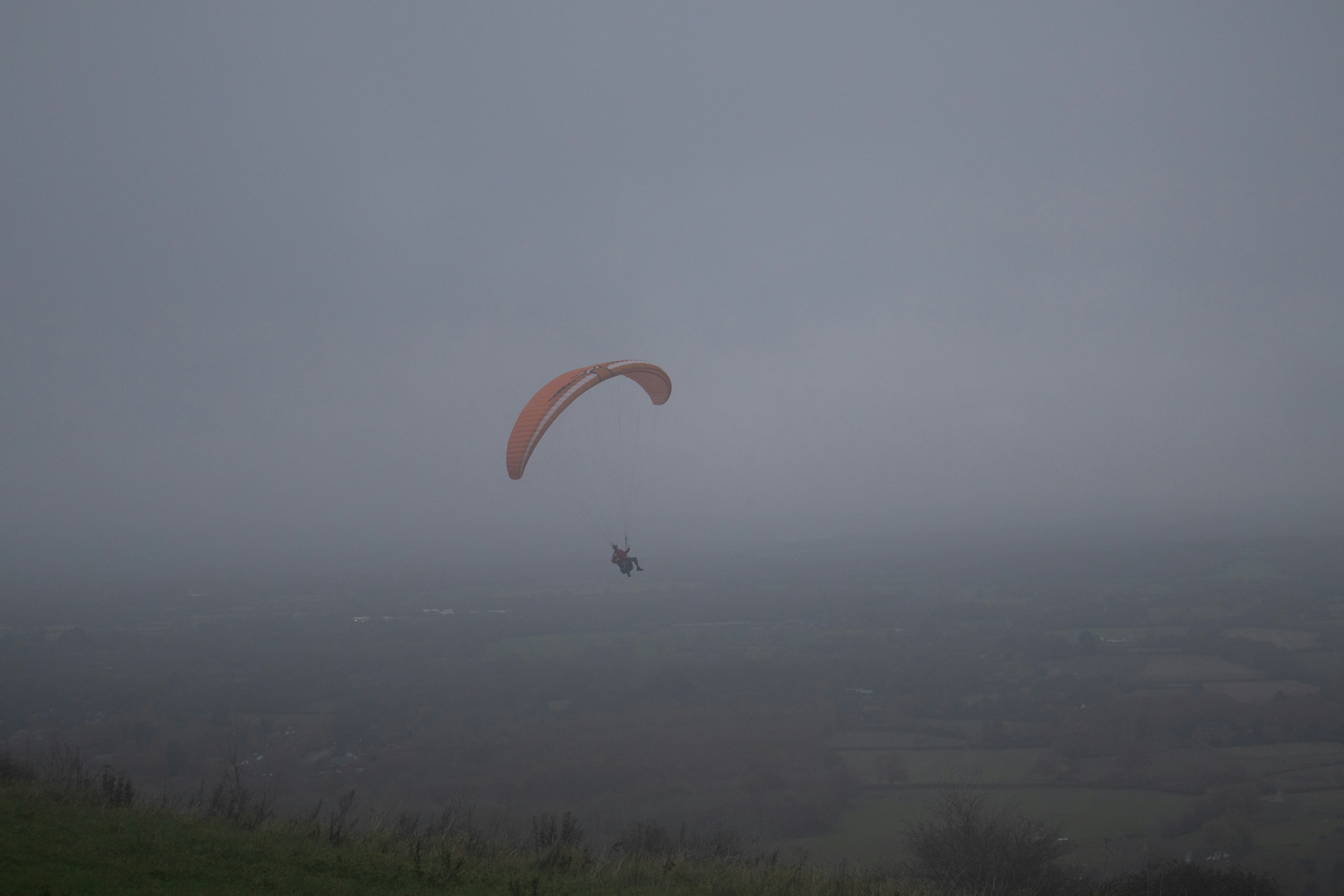 Orange Wing in the Mist: Paraglider Above a Quiet Moor