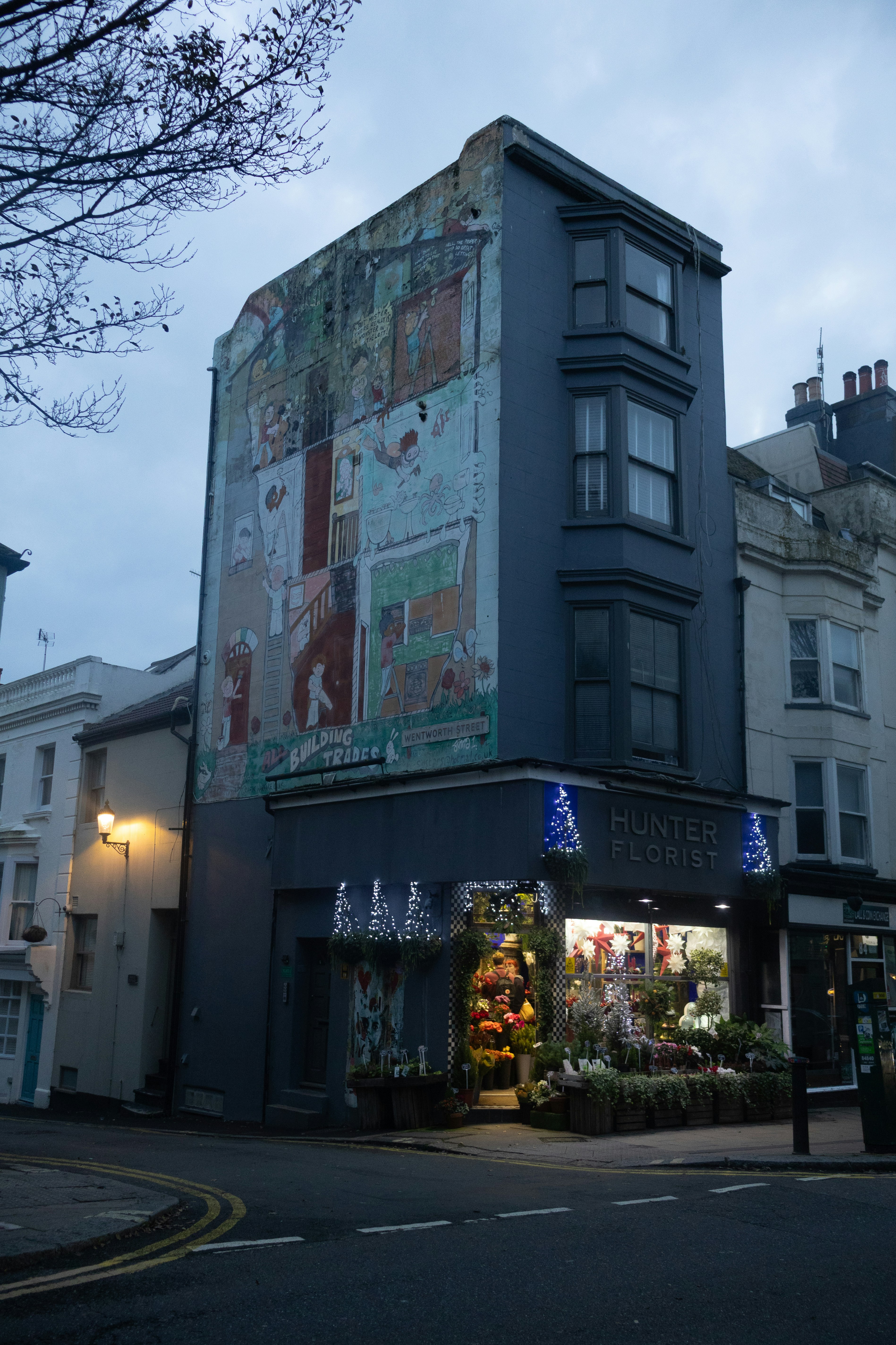 Blue-hour muraled facade crowns a cozy florist on a sleepy street