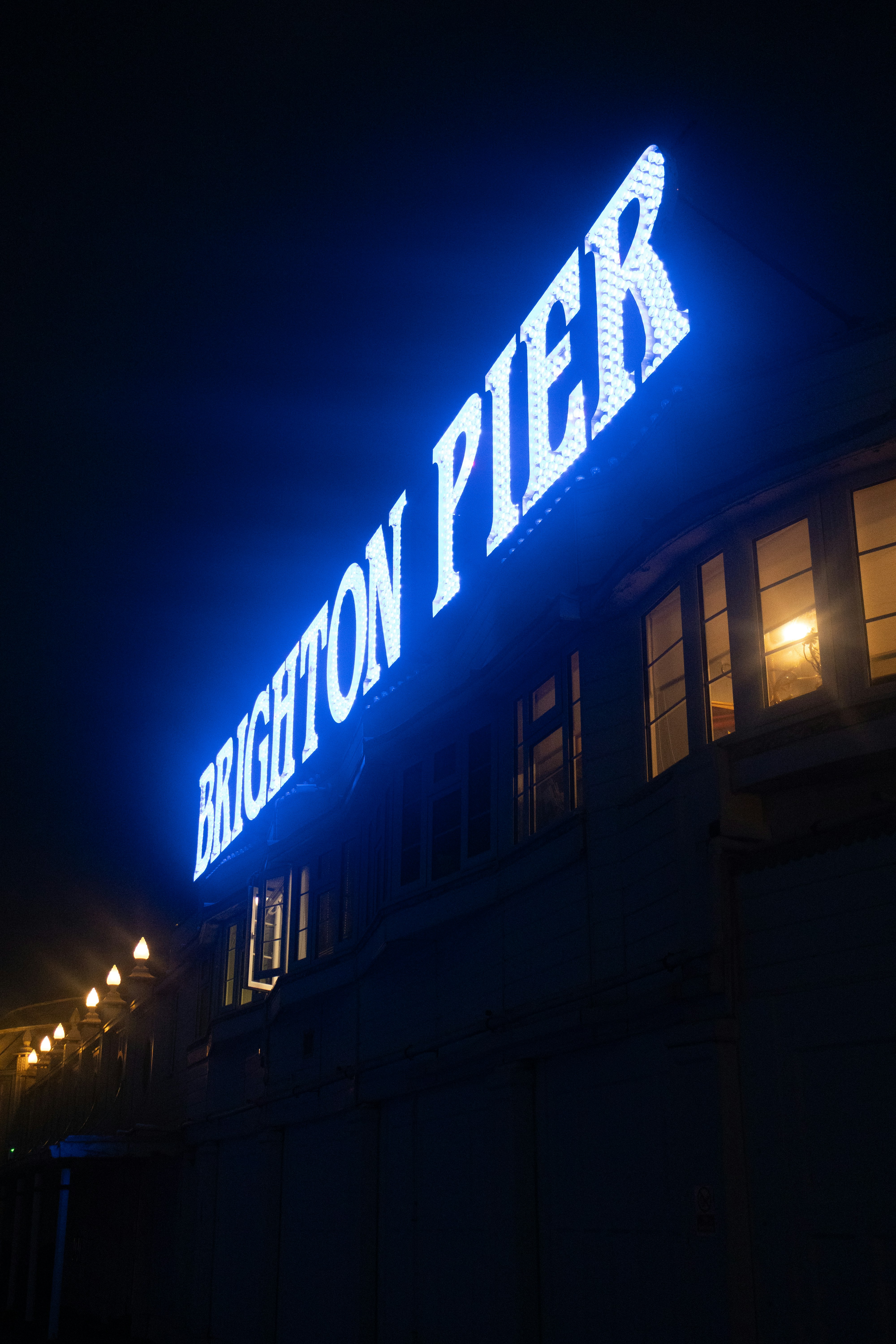 Blue Neon Crown Over Brighton Pier: Night Signage on a Quiet Facade