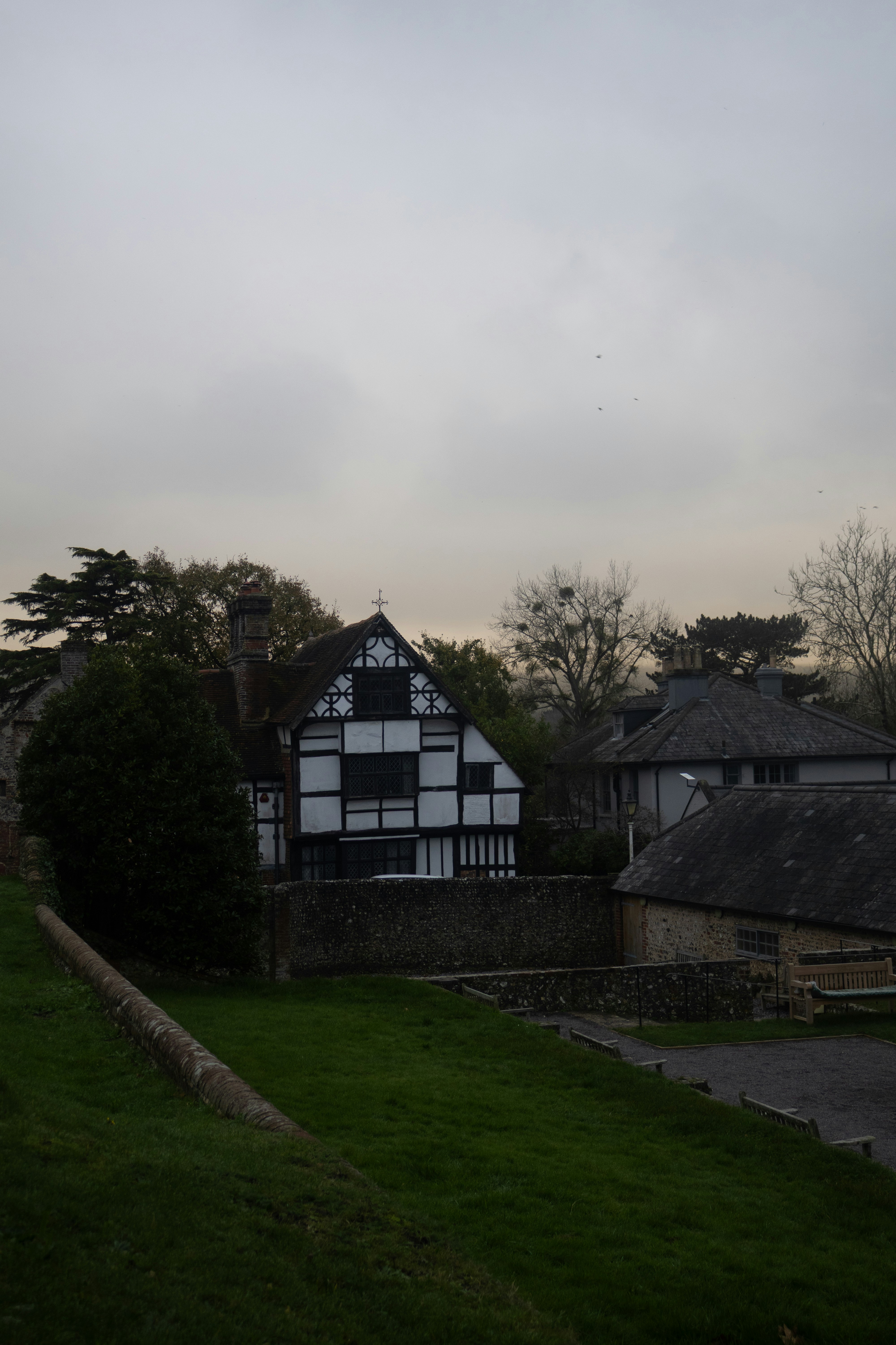 Timbered Quiet: A Tudor cottage glows beside a mossy stone wall at dusk