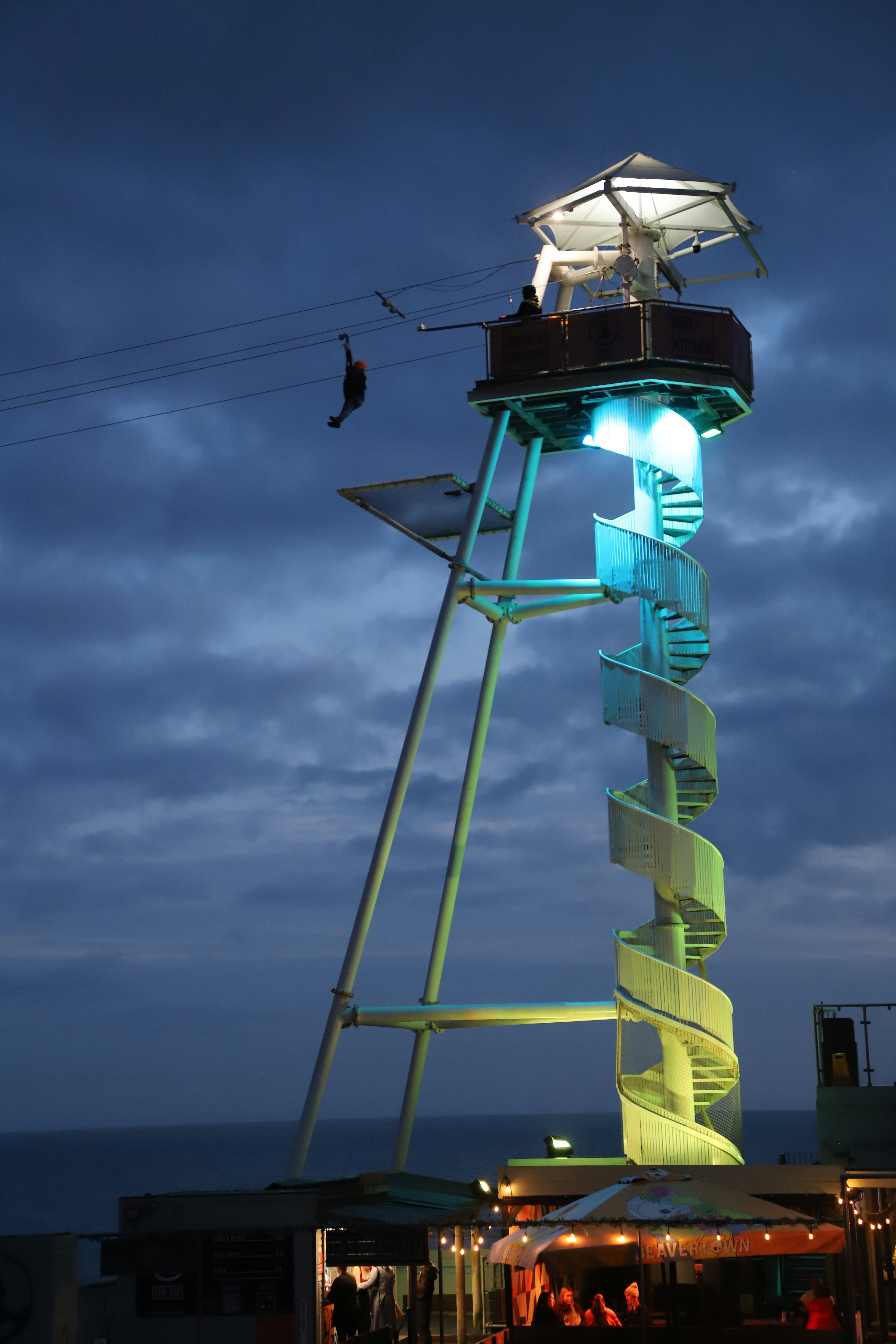Neon Spiral at Dusk: Zipline Silhouette Over the Pier