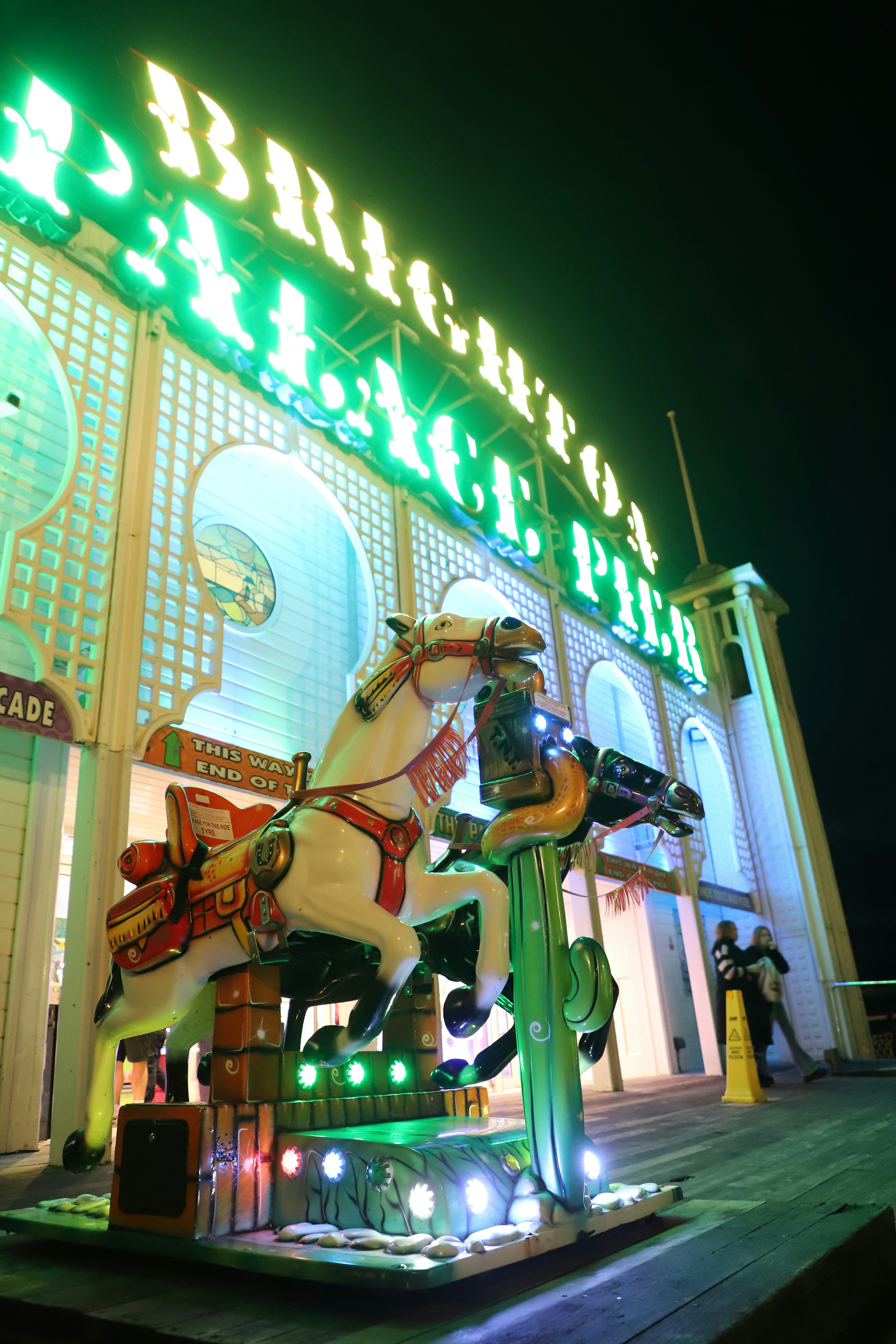 Neon Horses at Night: Carousel Under a Green Arcade Glow