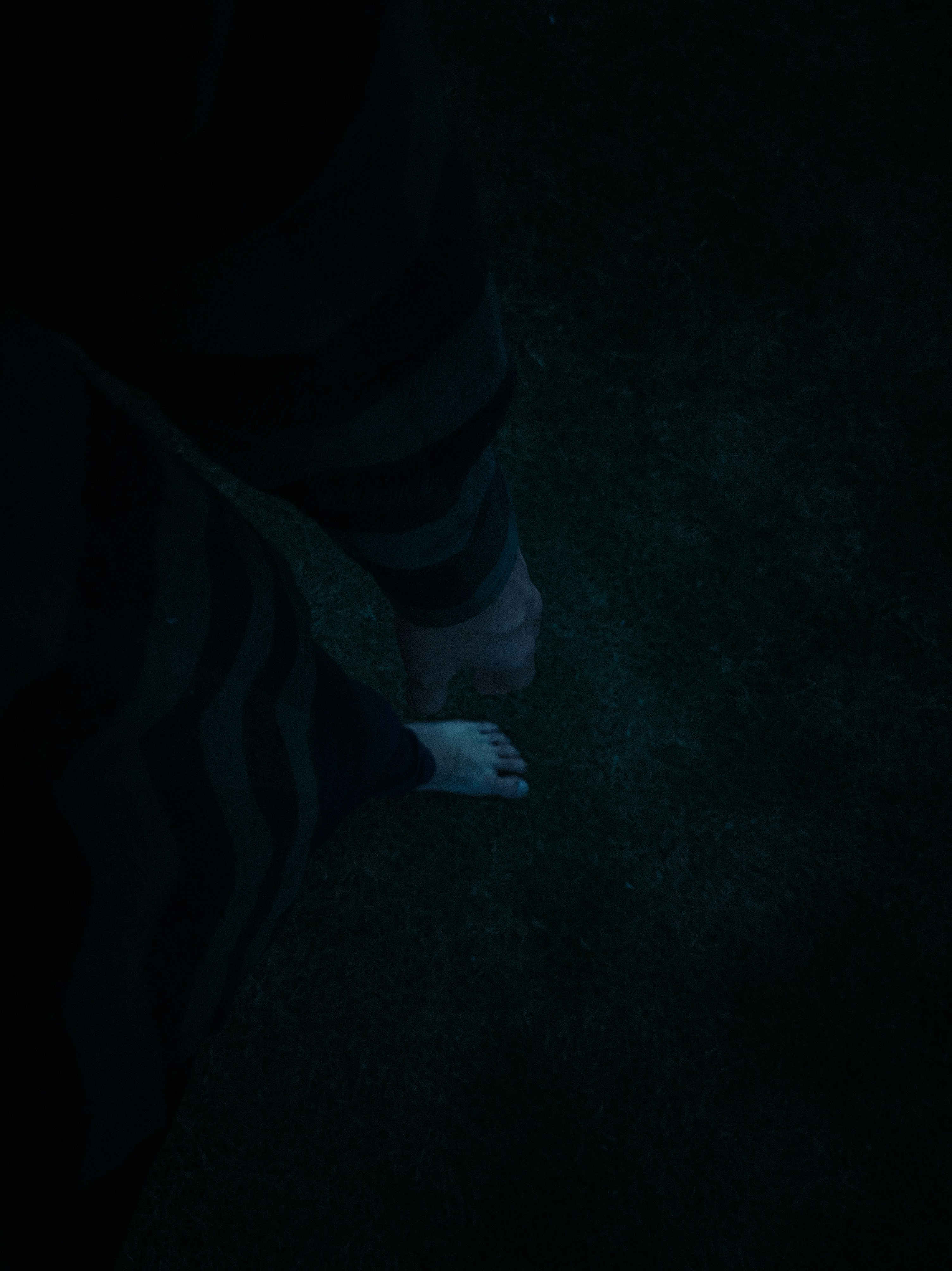 Bare foot stepping on grass in darkness