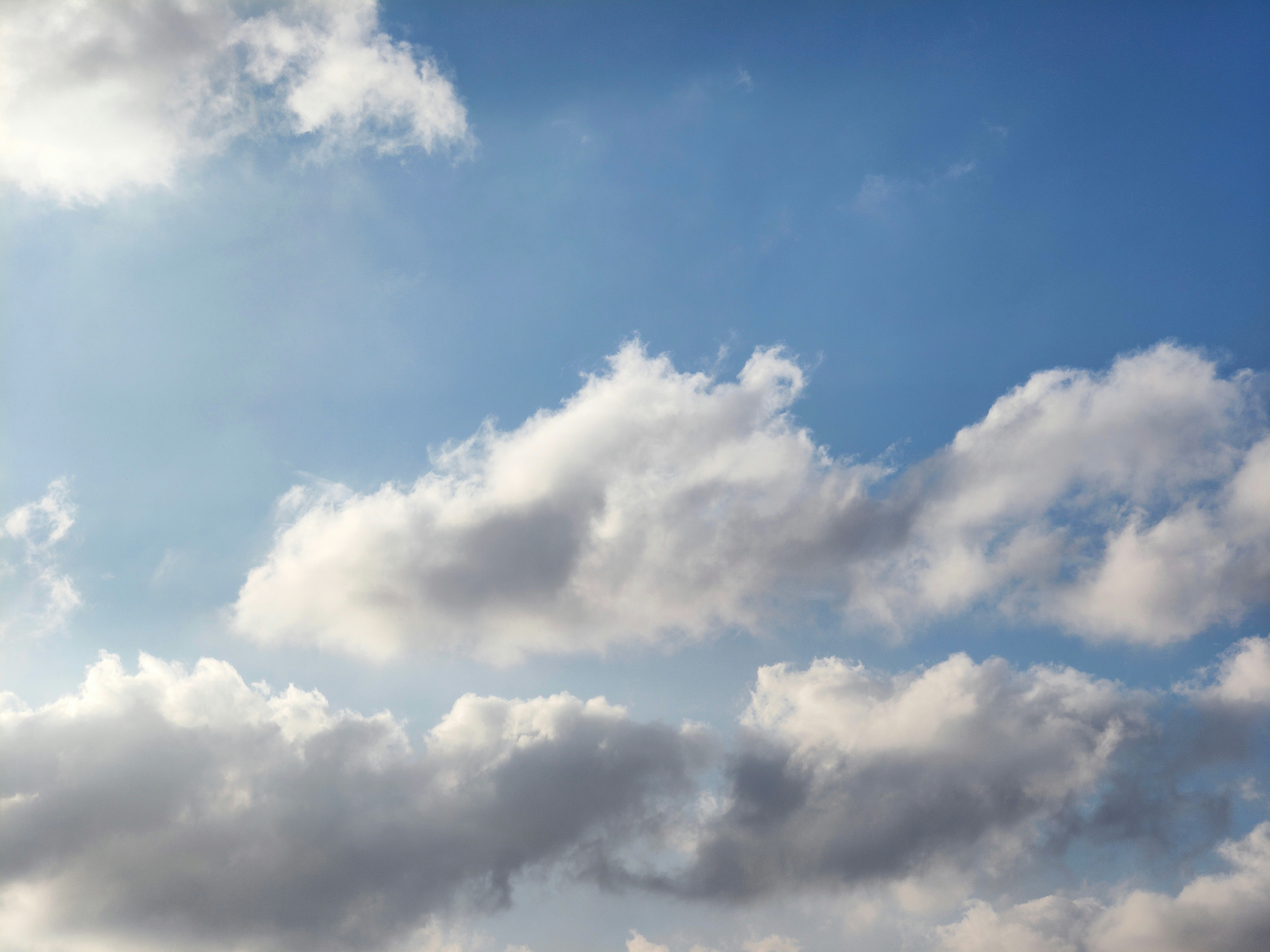Fluffy white clouds drift across a clear blue sky.