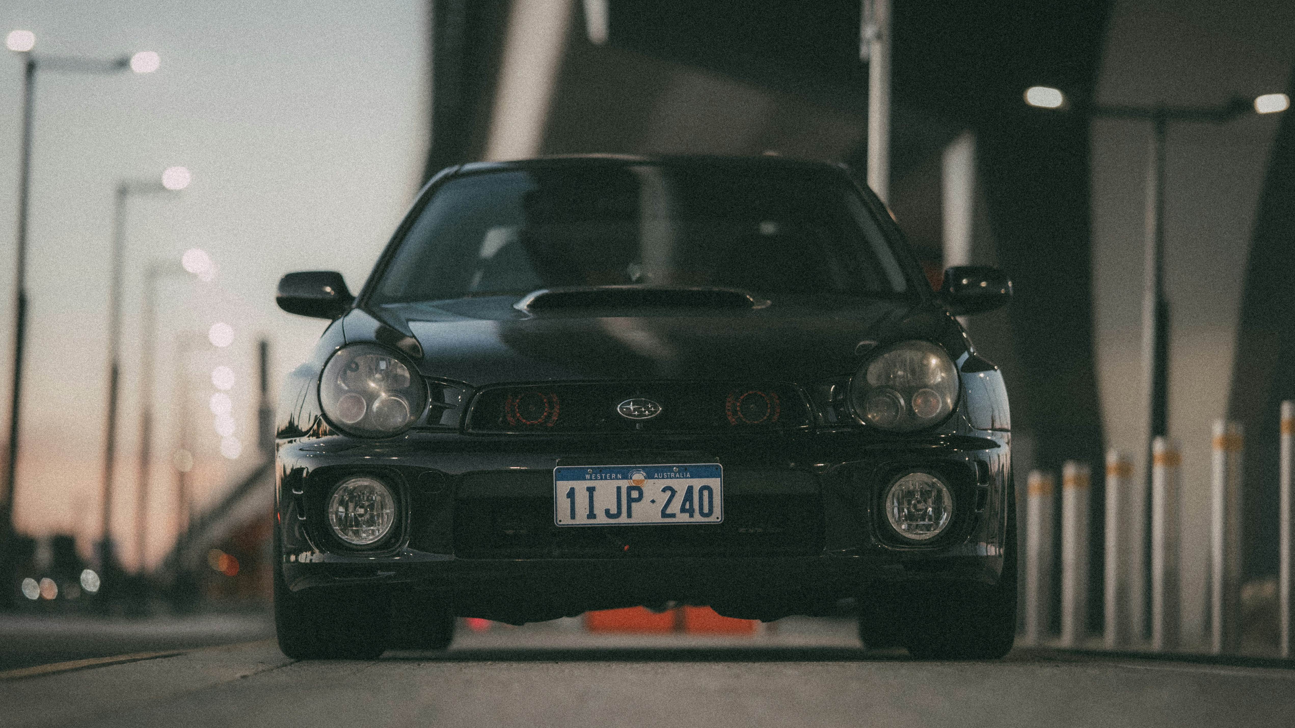 Neon Corridor Front View: A Black City Car Under Streetlights