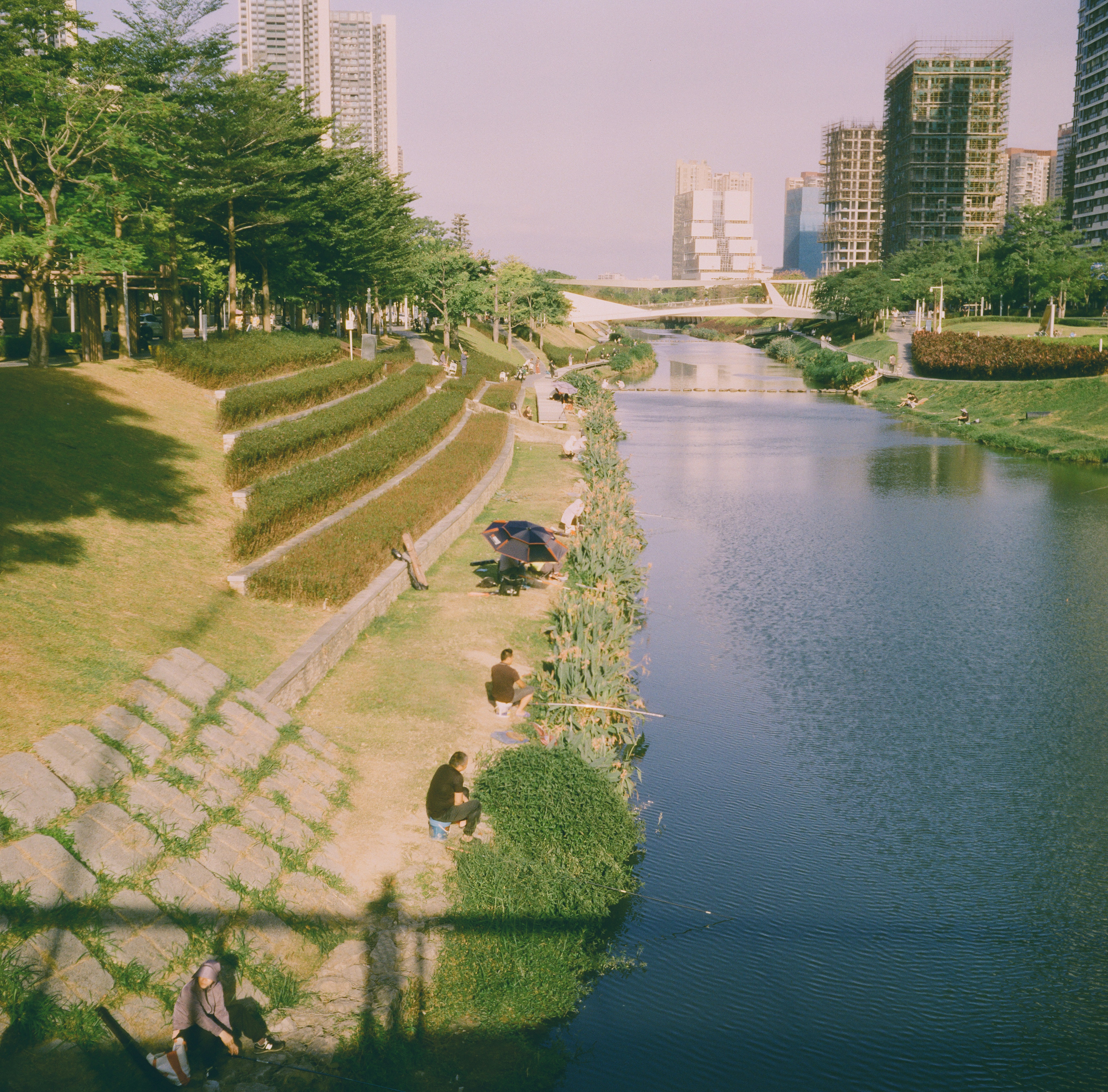 A warm afternoon—the riverbank is filled with people fishing, along with my shadow.