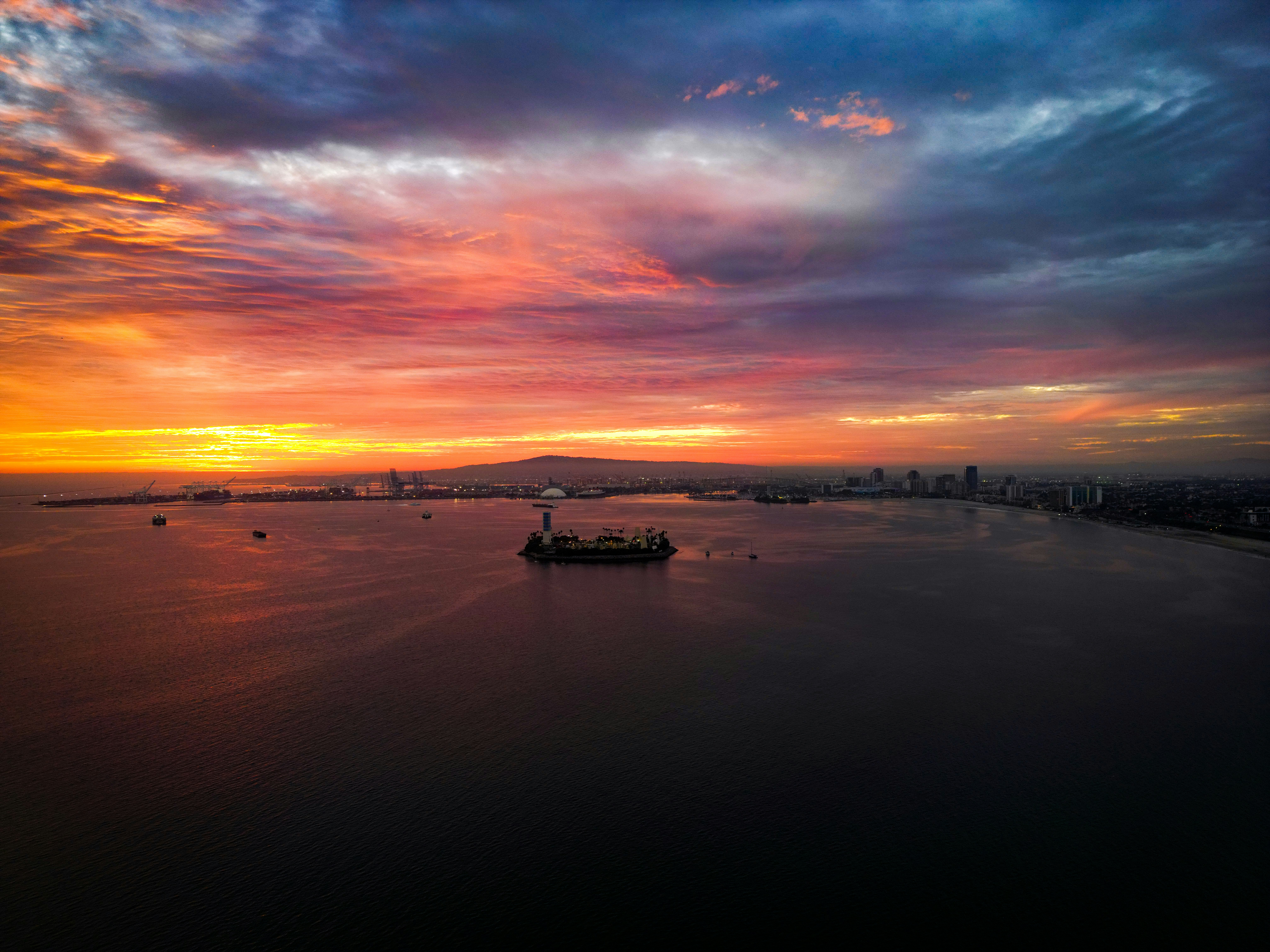 Dramatic sunset over a city skyline and calm ocean.