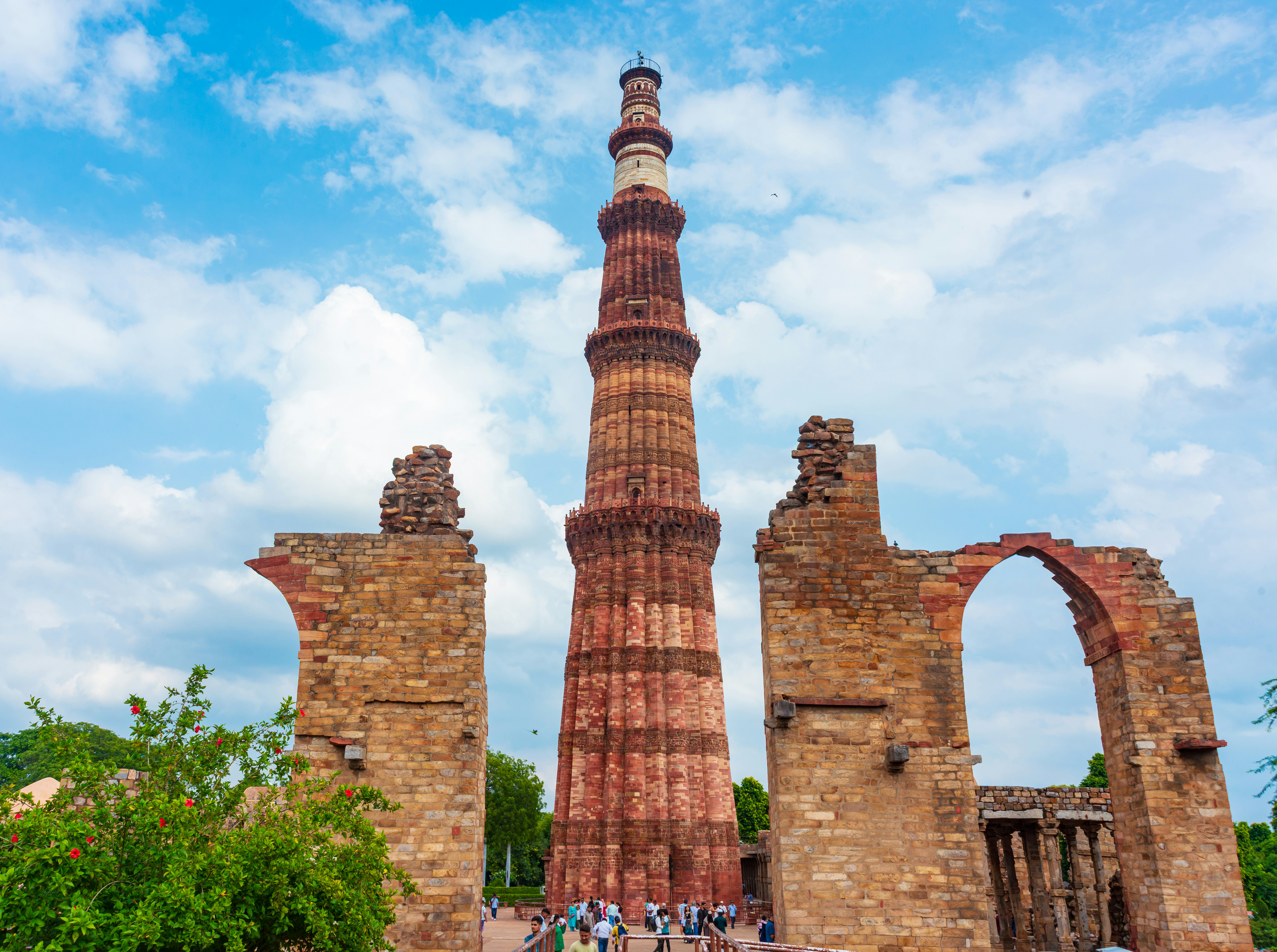 Red-brick Sentinel: A towering minaret framed by ancient arches against a flawless blue sky
