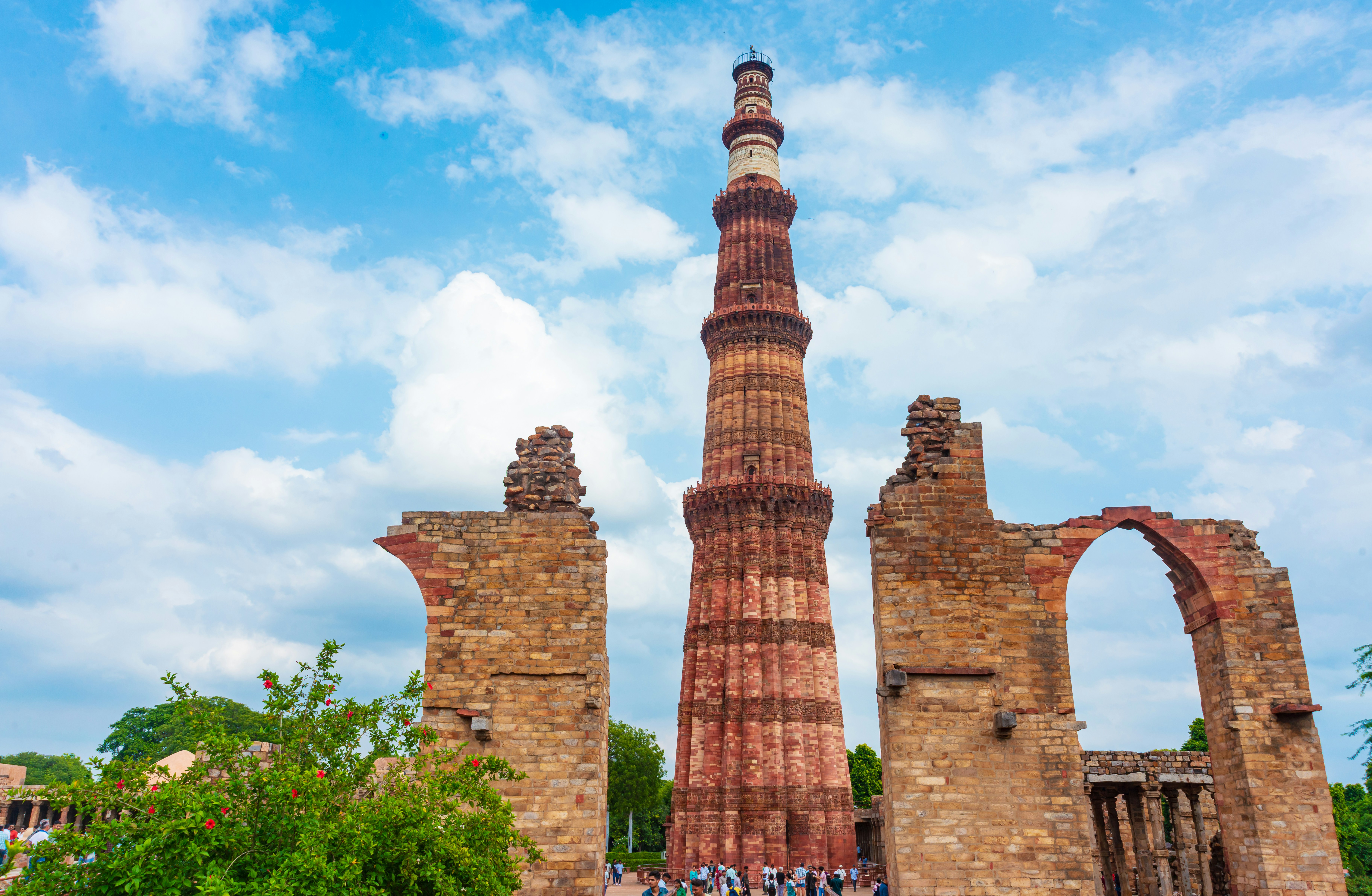 Ruins and a towering minaret under a bright sky