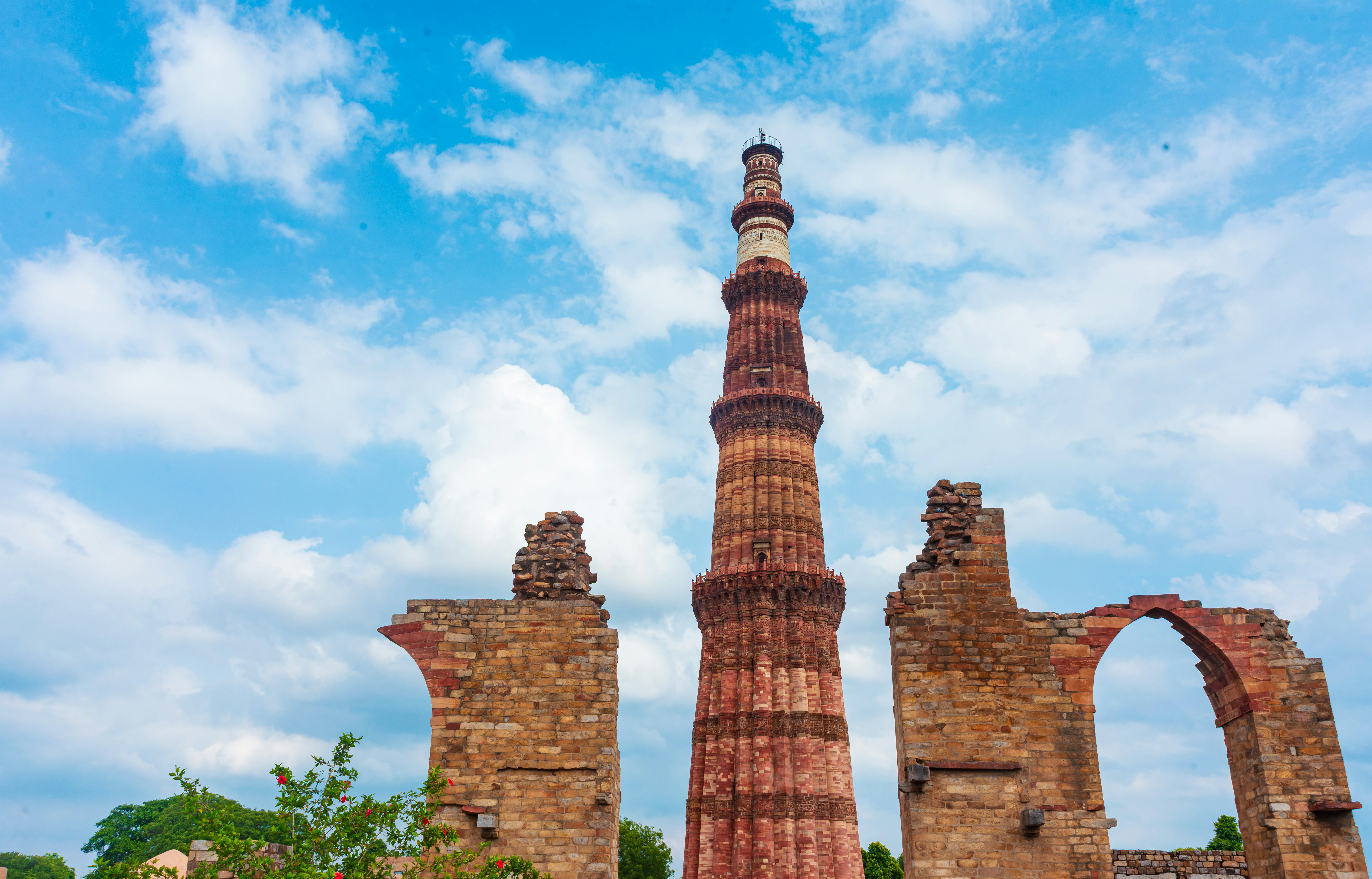 Qutub Minar is a UNESCO World Heritage Site in Mehrauli built between 1199 and 1220 on the grounds of Lal Kot, Delhi’s earliest fortified city. Qutb ud din Aibak began it after defeating Prithviraj Chauhan and later Sultanate rulers completed it with Firuz Shah Tughlaq rebuilding the upper section in 1368. The tower rises seventy three metres with three hundred ninety nine steps and displays fluted sandstone, carved bands, and Hindu Islamic design influences created by Hindu craftsmen under Muslim architects.