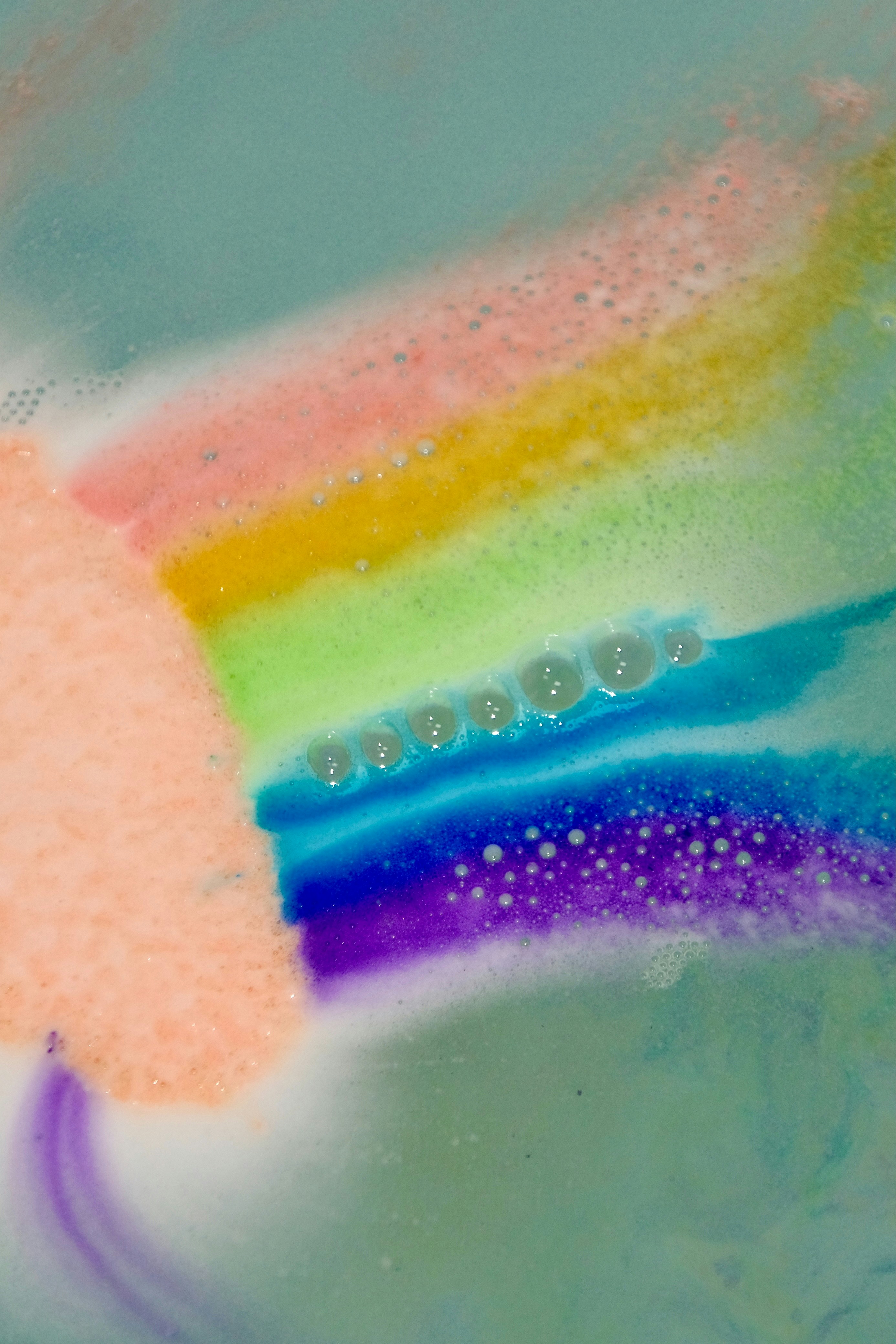 Colorful bath bomb dissolving in water with bubbles.