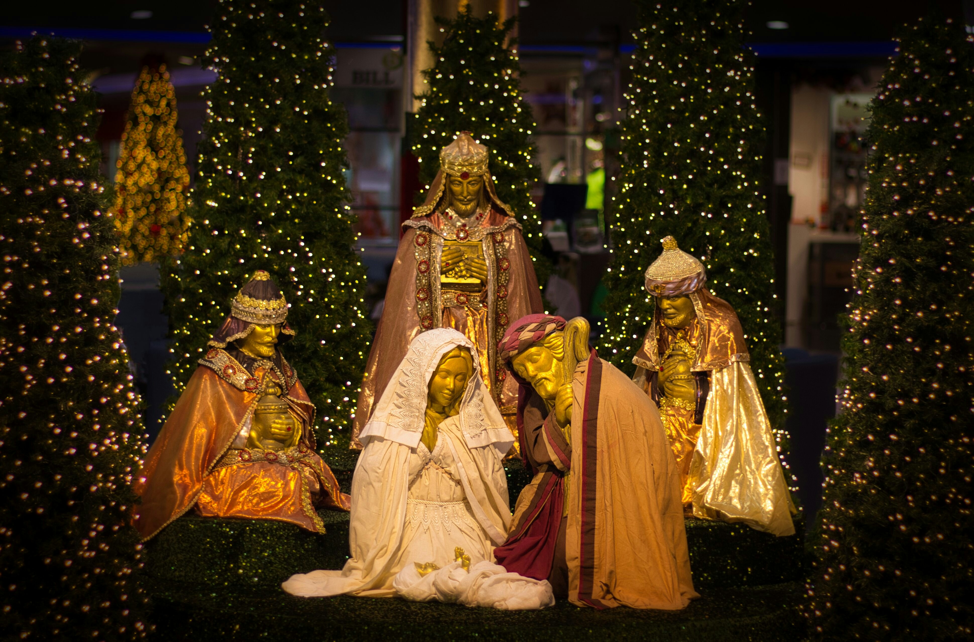 A warm, glowing nativity scene with Mary, Joseph, the Wise Men, and Christmas trees illuminated by festive lights. A peaceful holiday display perfect for Christmas and seasonal content.