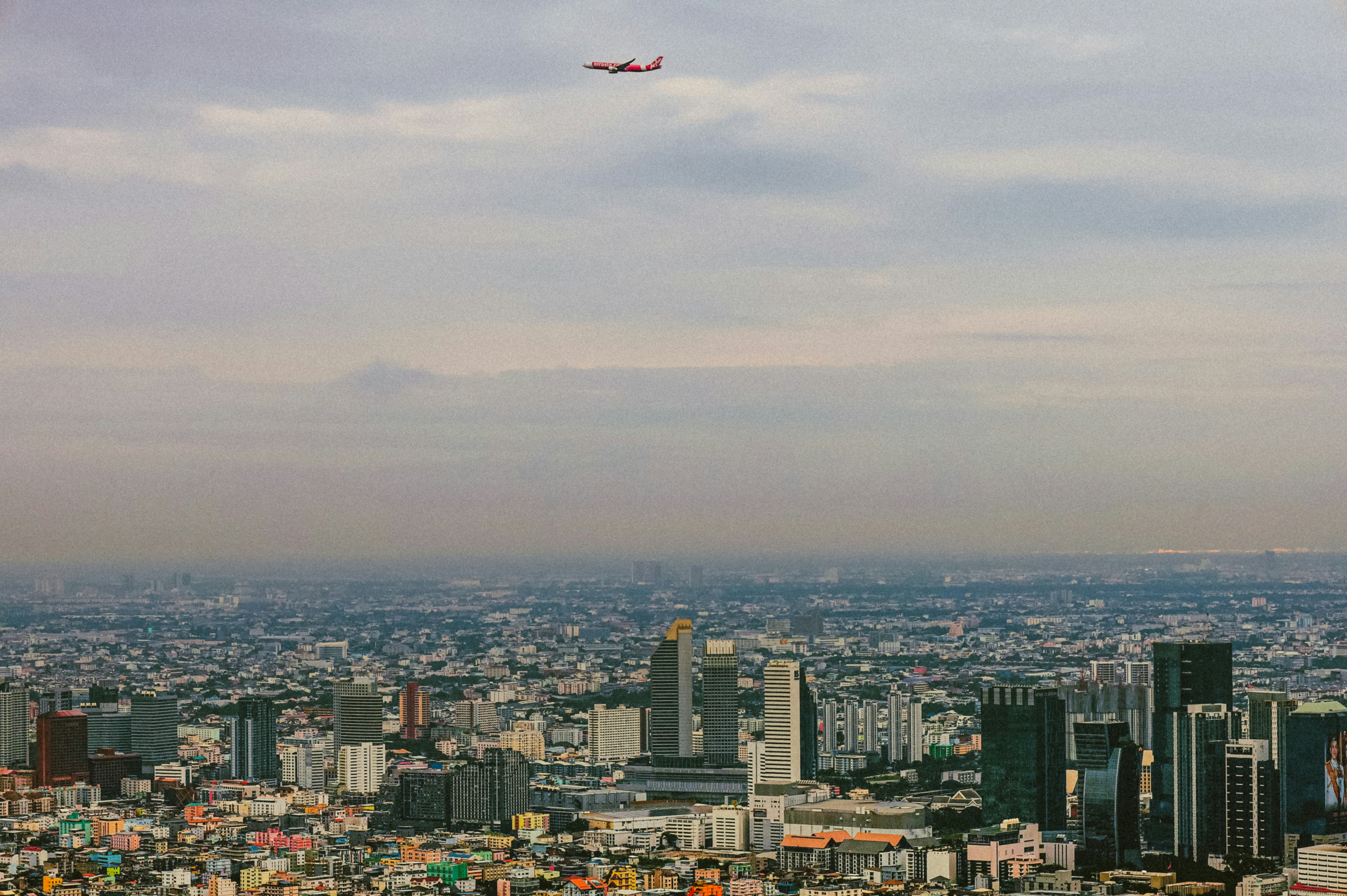 City in the Distance: Aerial View with a Red Jet Crossing the Horizon