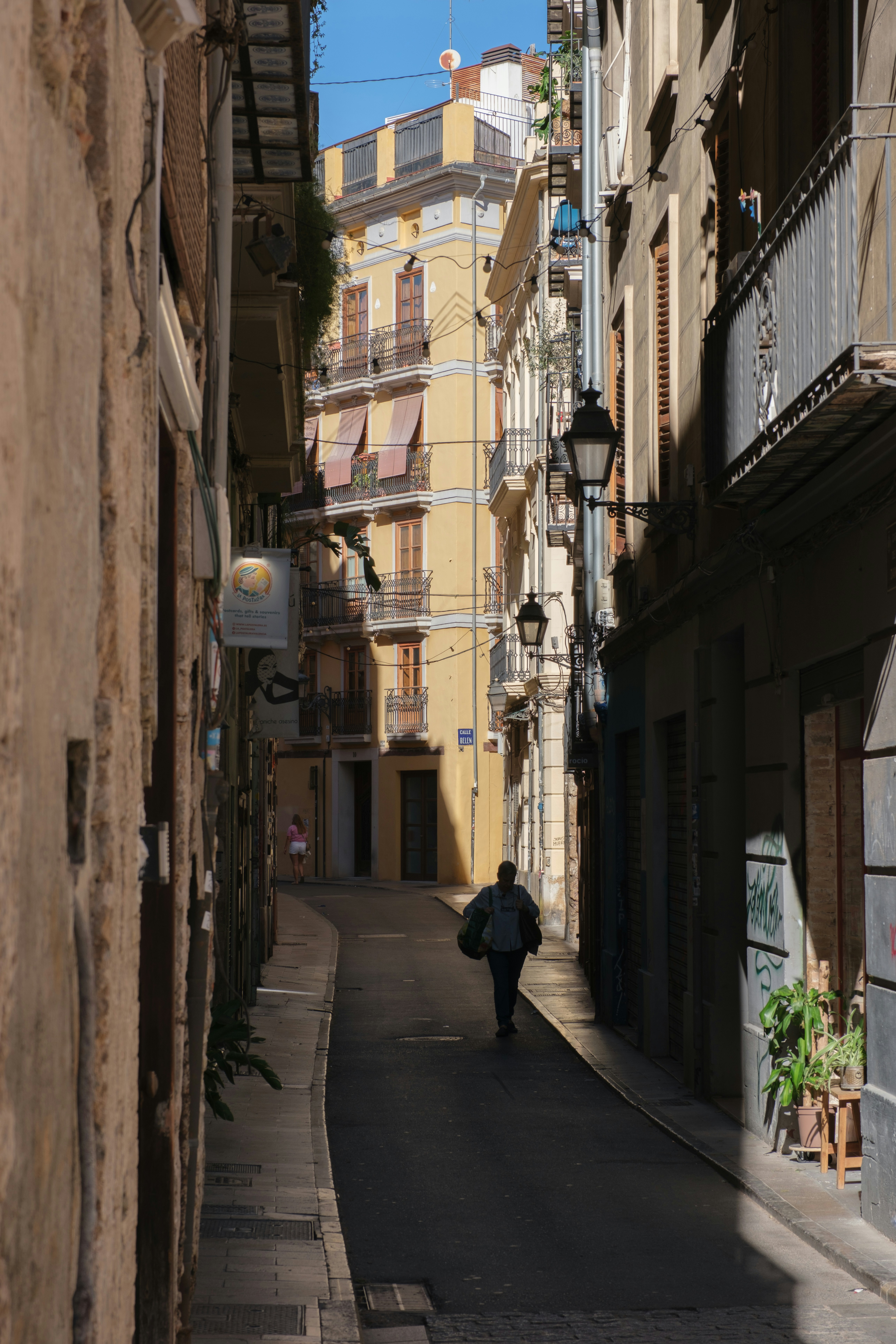 Calle de Luz: A Sunlit Alley Framed by Balconies and a Lone Pedestrian