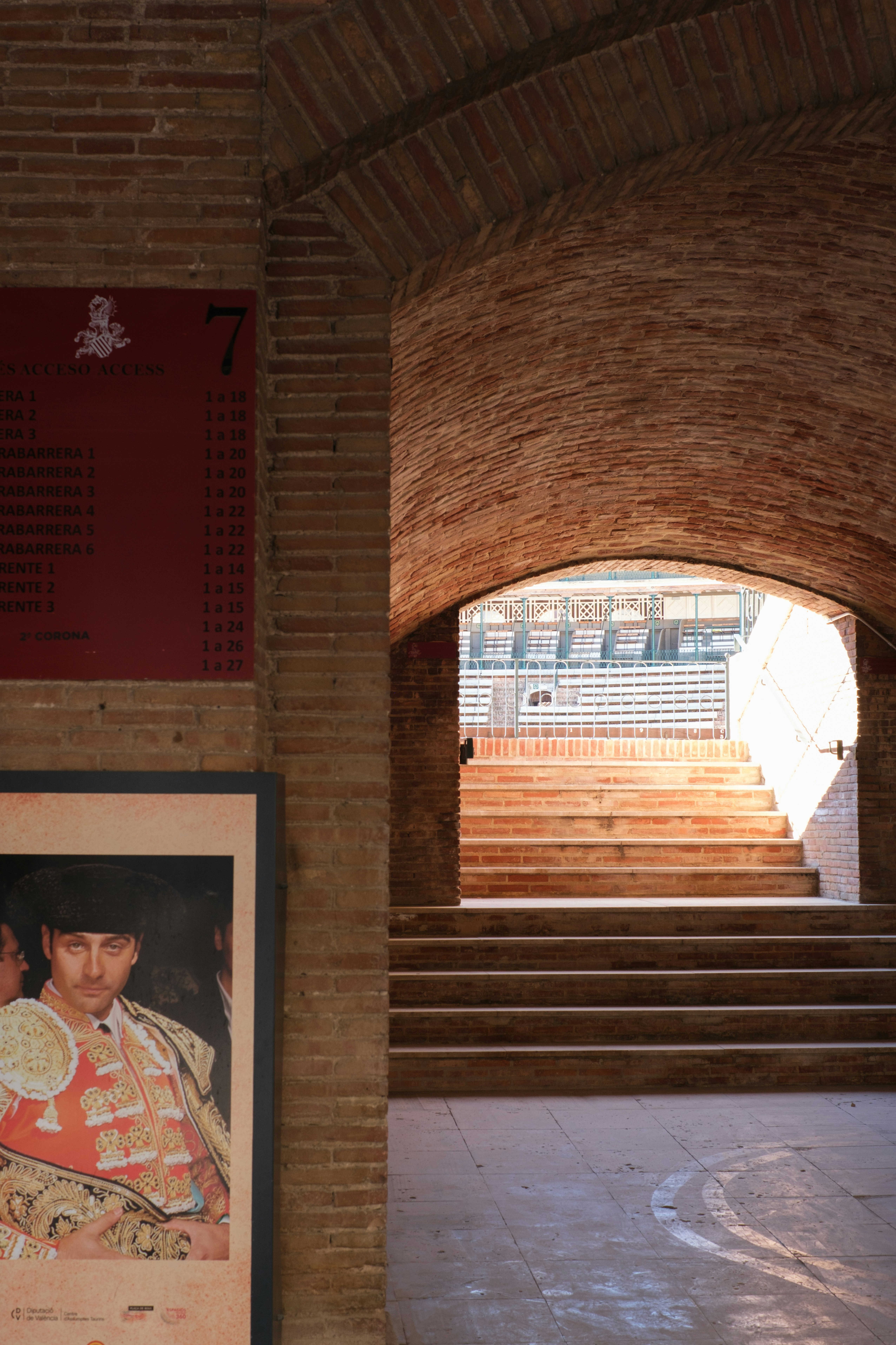 Archway to Daylight: Sunlit Steps Beckon Beyond a Brick Corridor