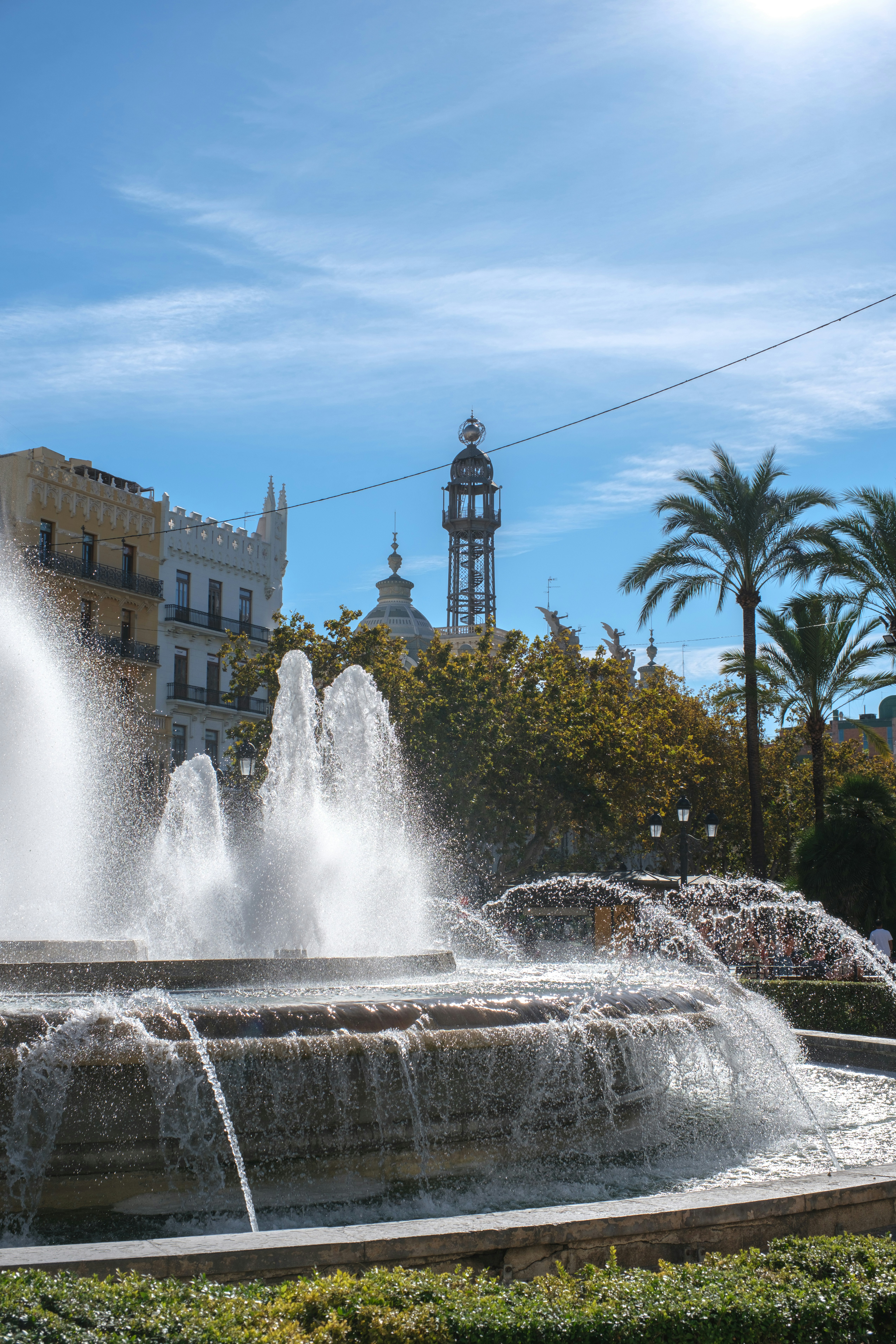 Fountain Currents Beneath a Clocktower: A Palm-Fringed City Square